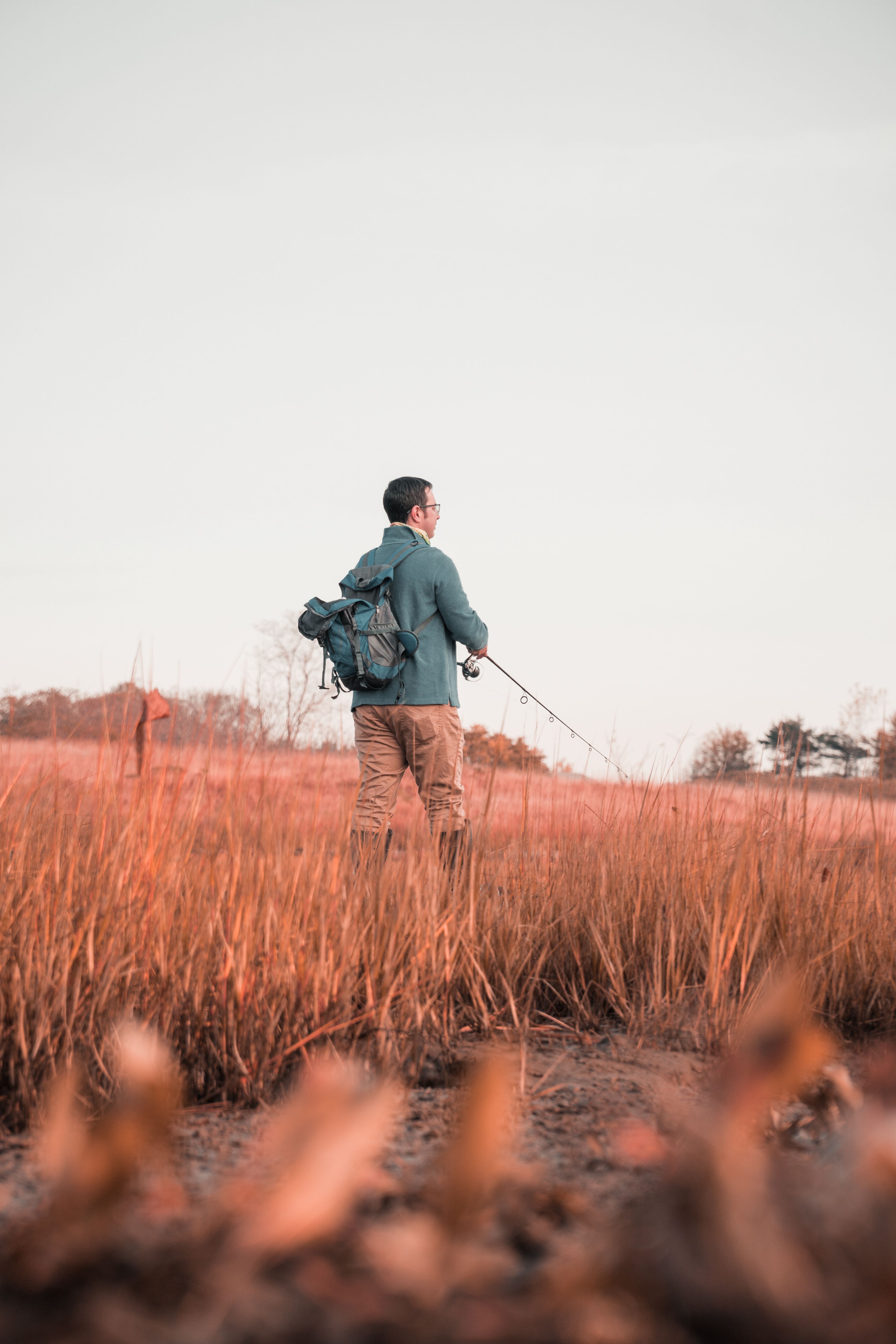 Man walking on Brown Grass holding a Fishing Pole · Free Stock Photo