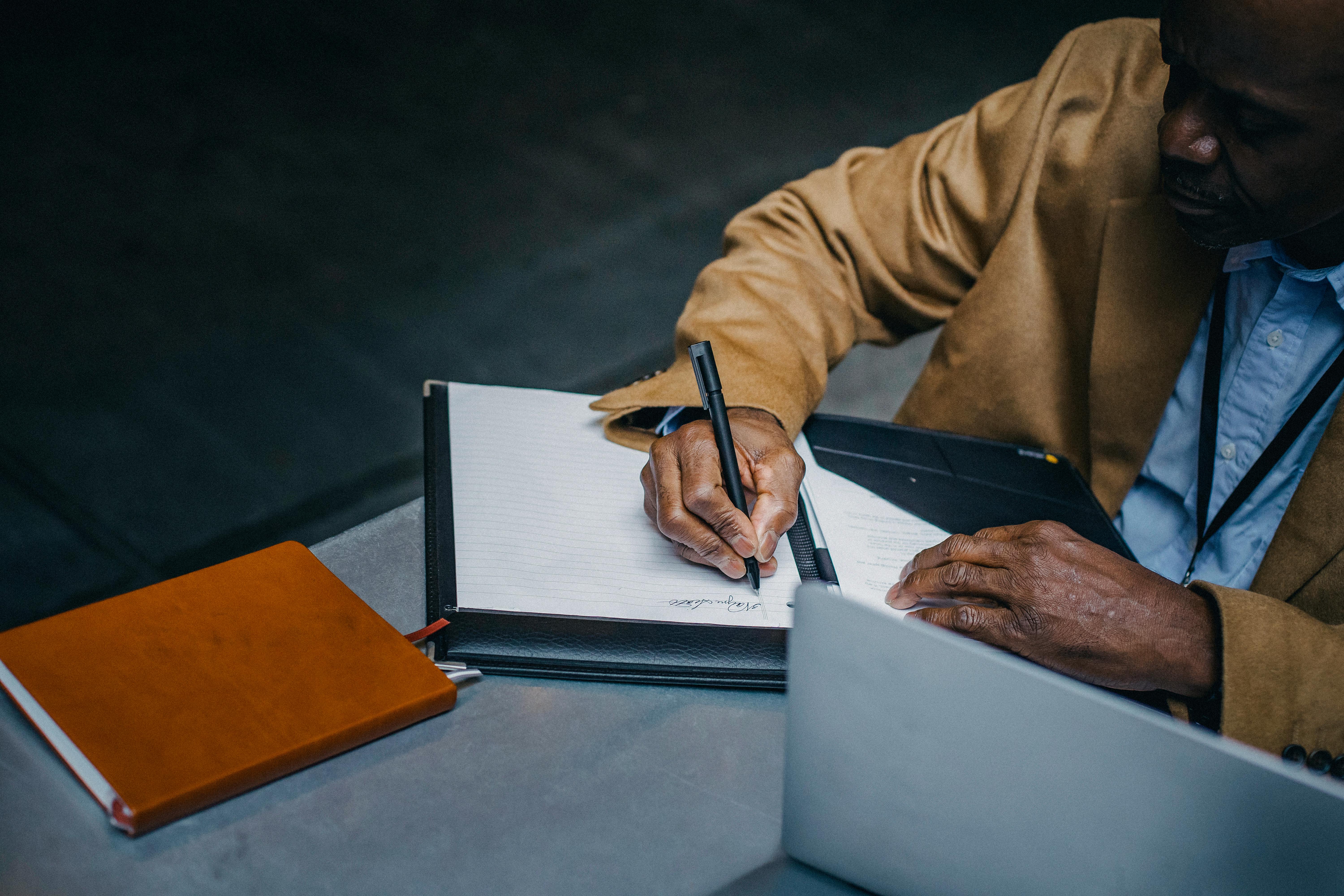 Crop ethnic businessman taking note on paper sheet at table · Free ...