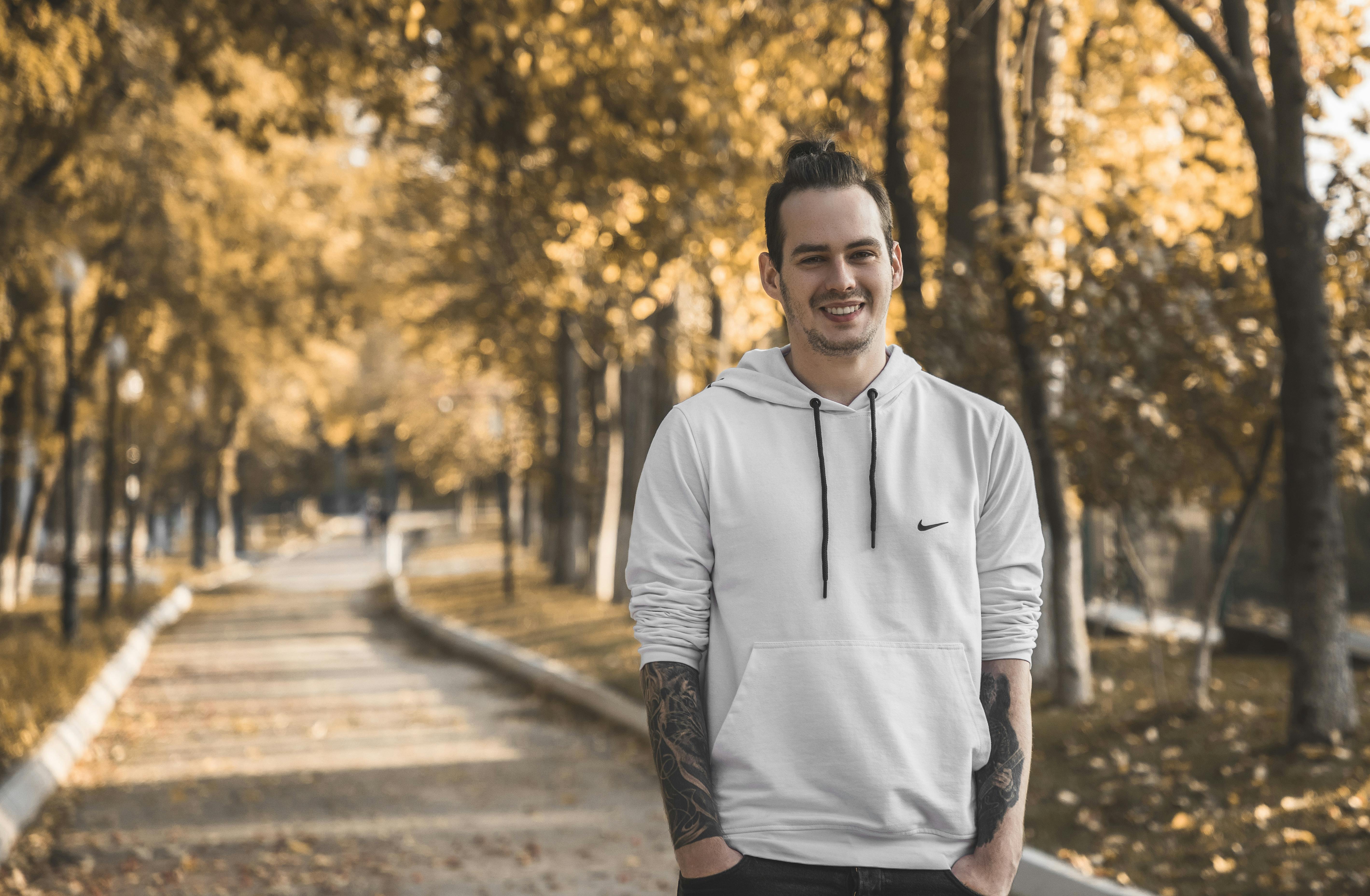 Laughing man in hoodie standing in park · Free Stock Photo