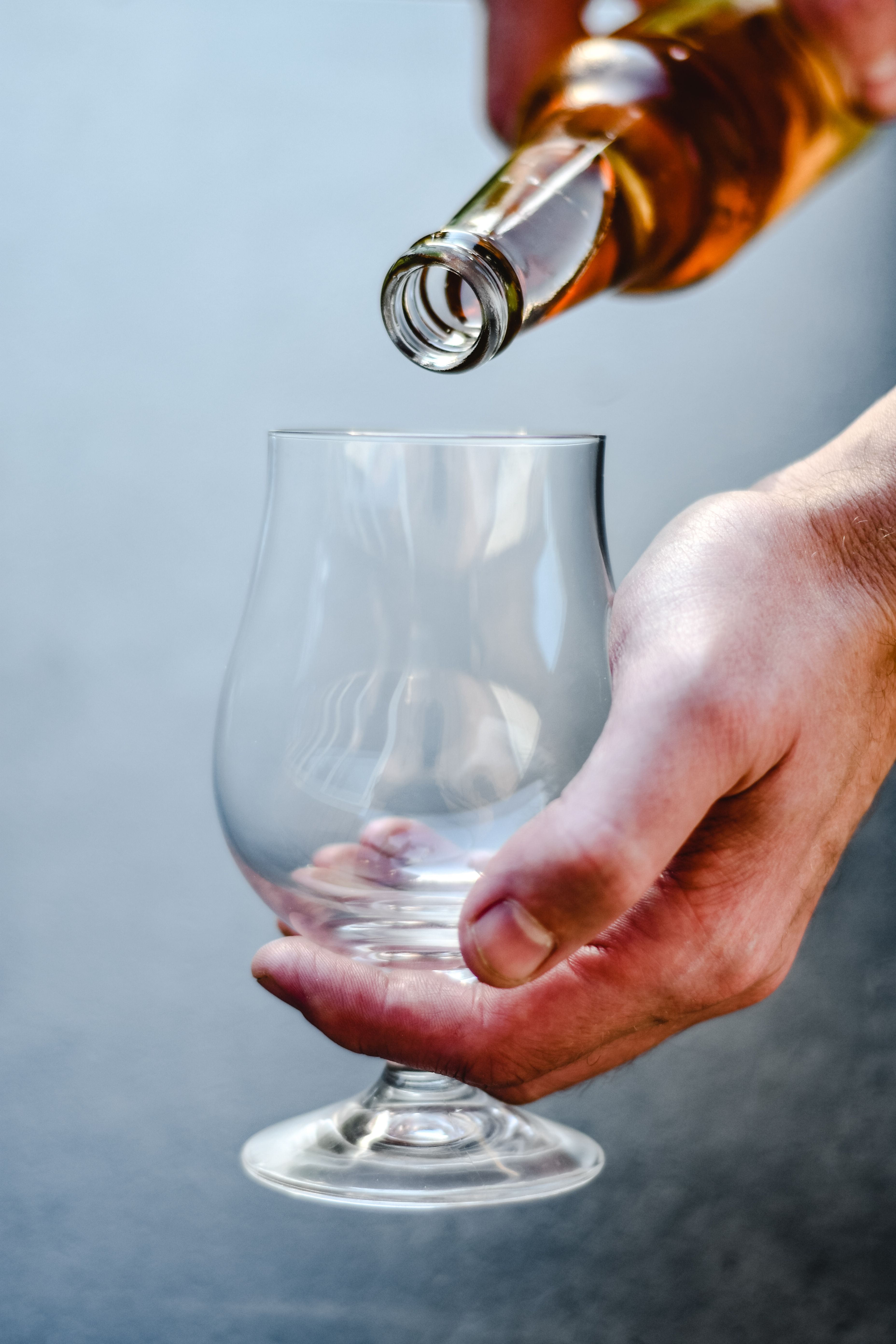 A Hand Pouring Brown Liquid on a Glass · Free Stock Photo