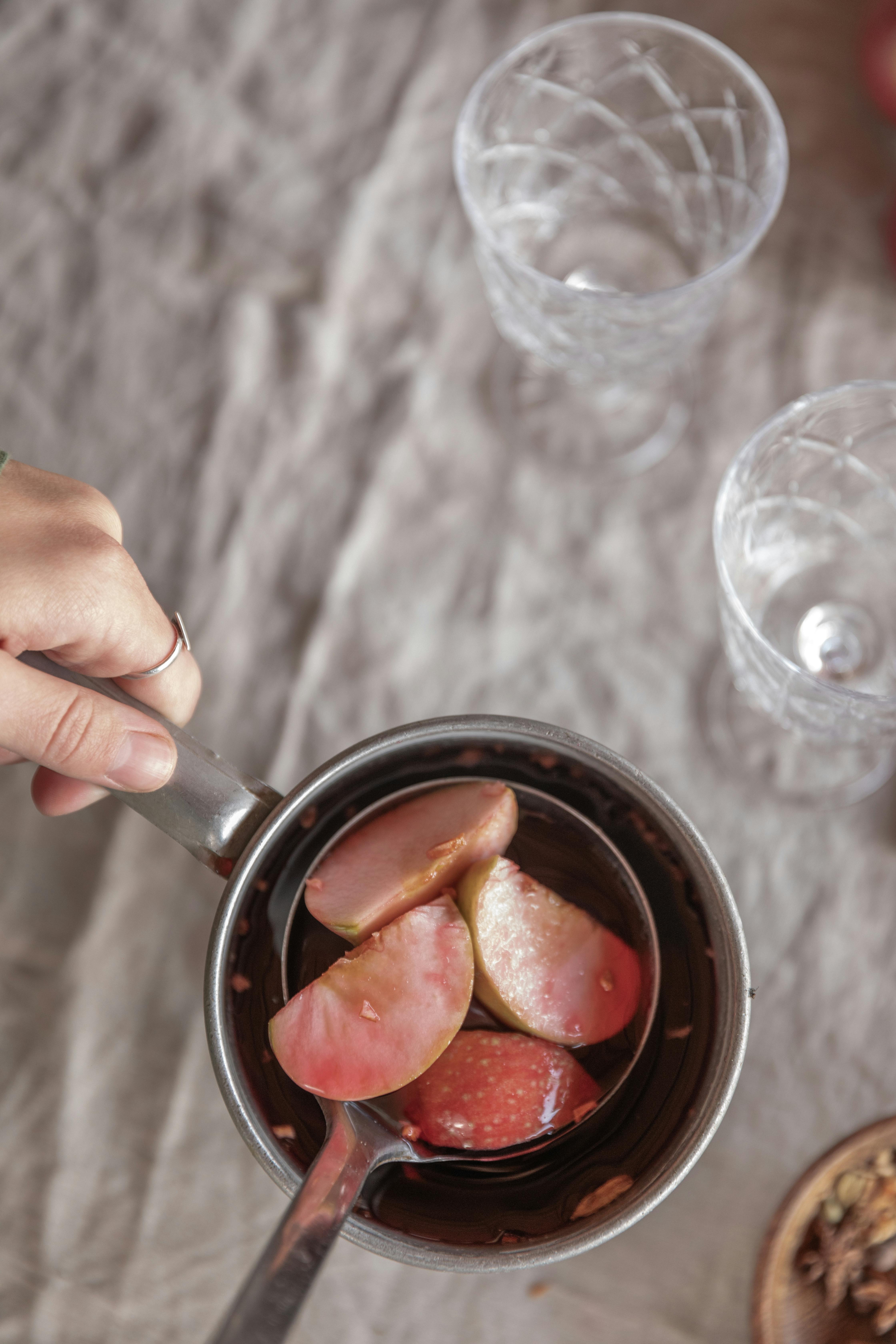Person Holding a Metal Ladle with Slices of Apples · Free Stock Photo