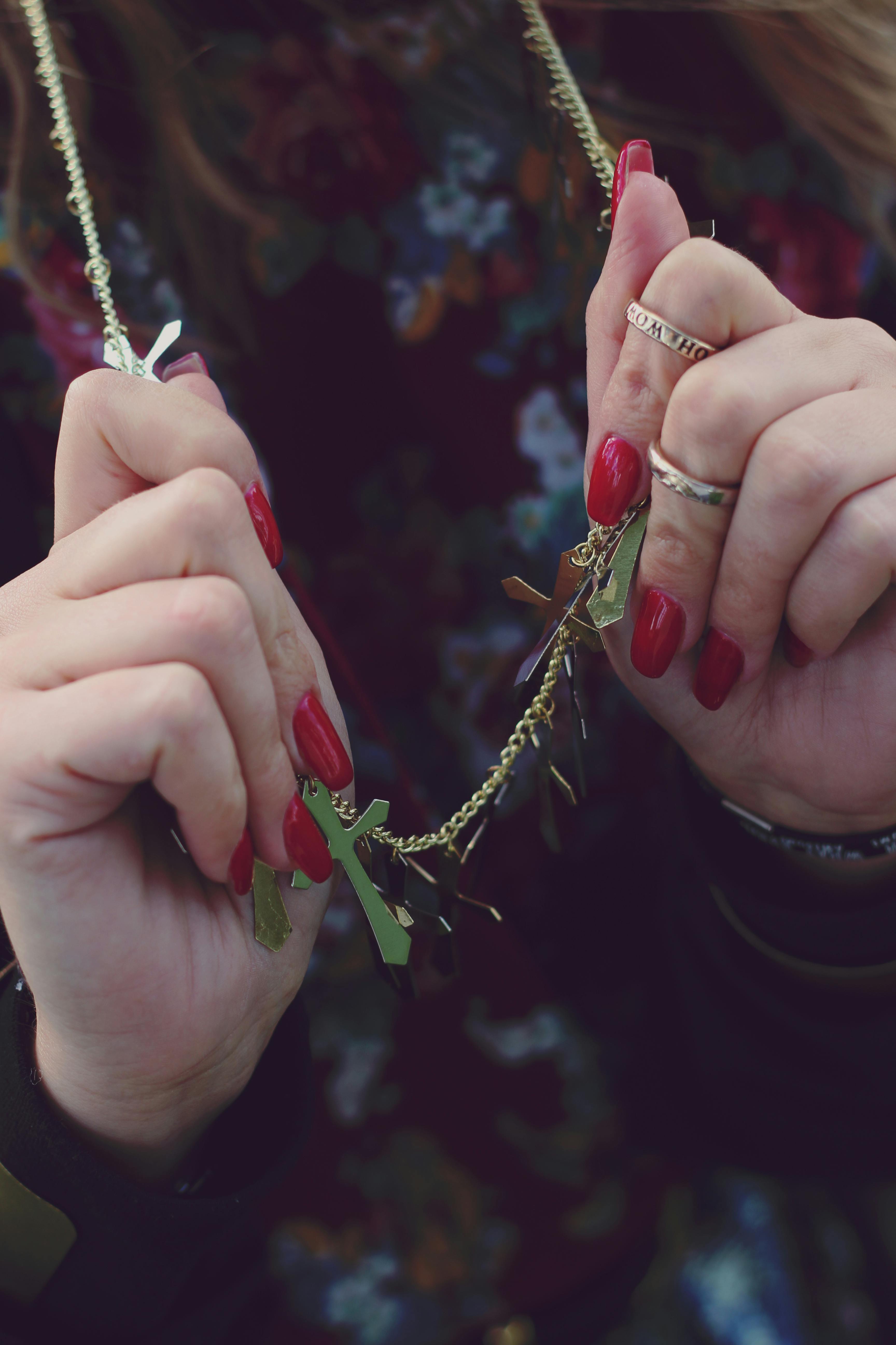 Red nails, cross jewelry & rings · Free Stock Photo
