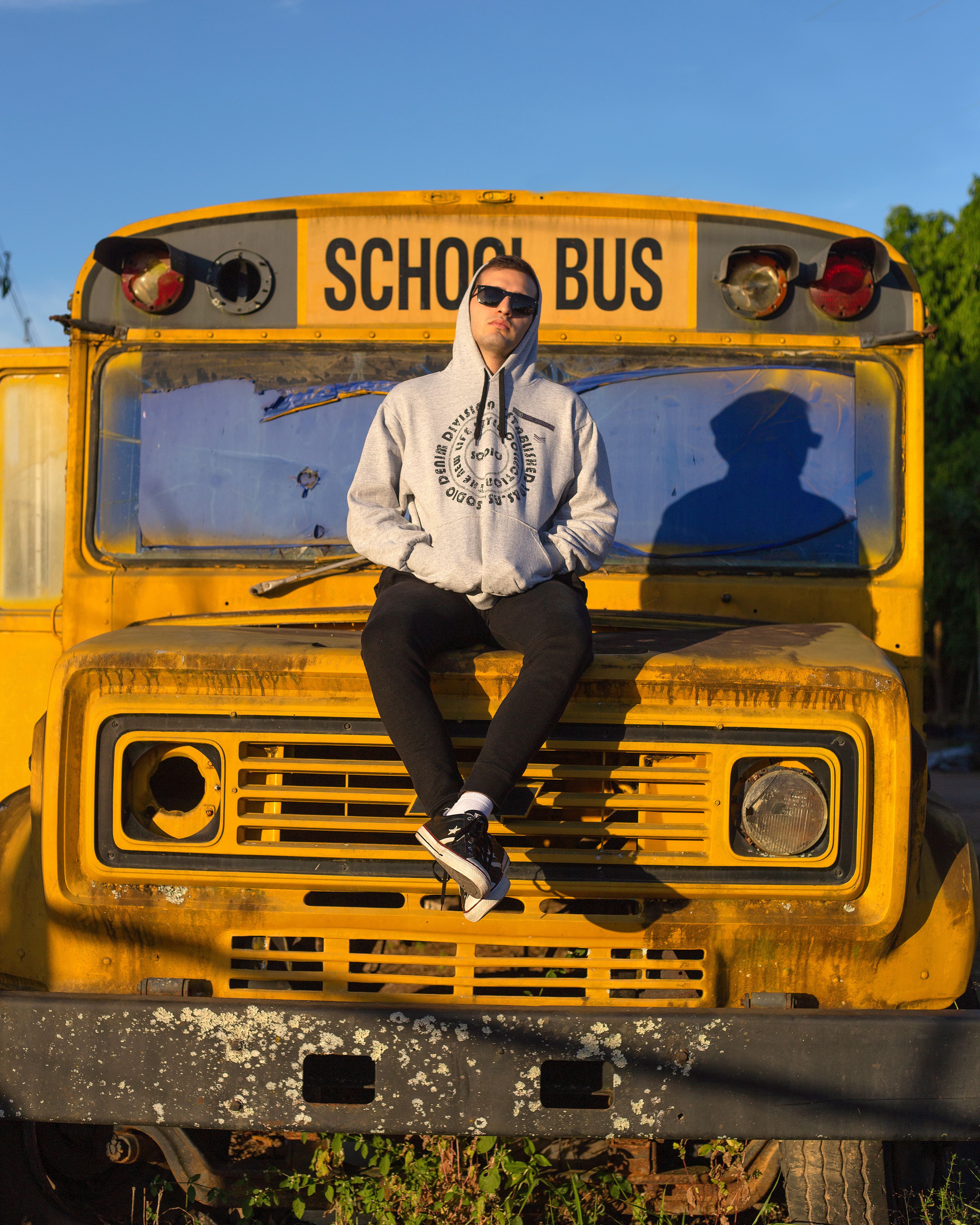 Man Sitting on a Hood of a School Bus · Free Stock Photo