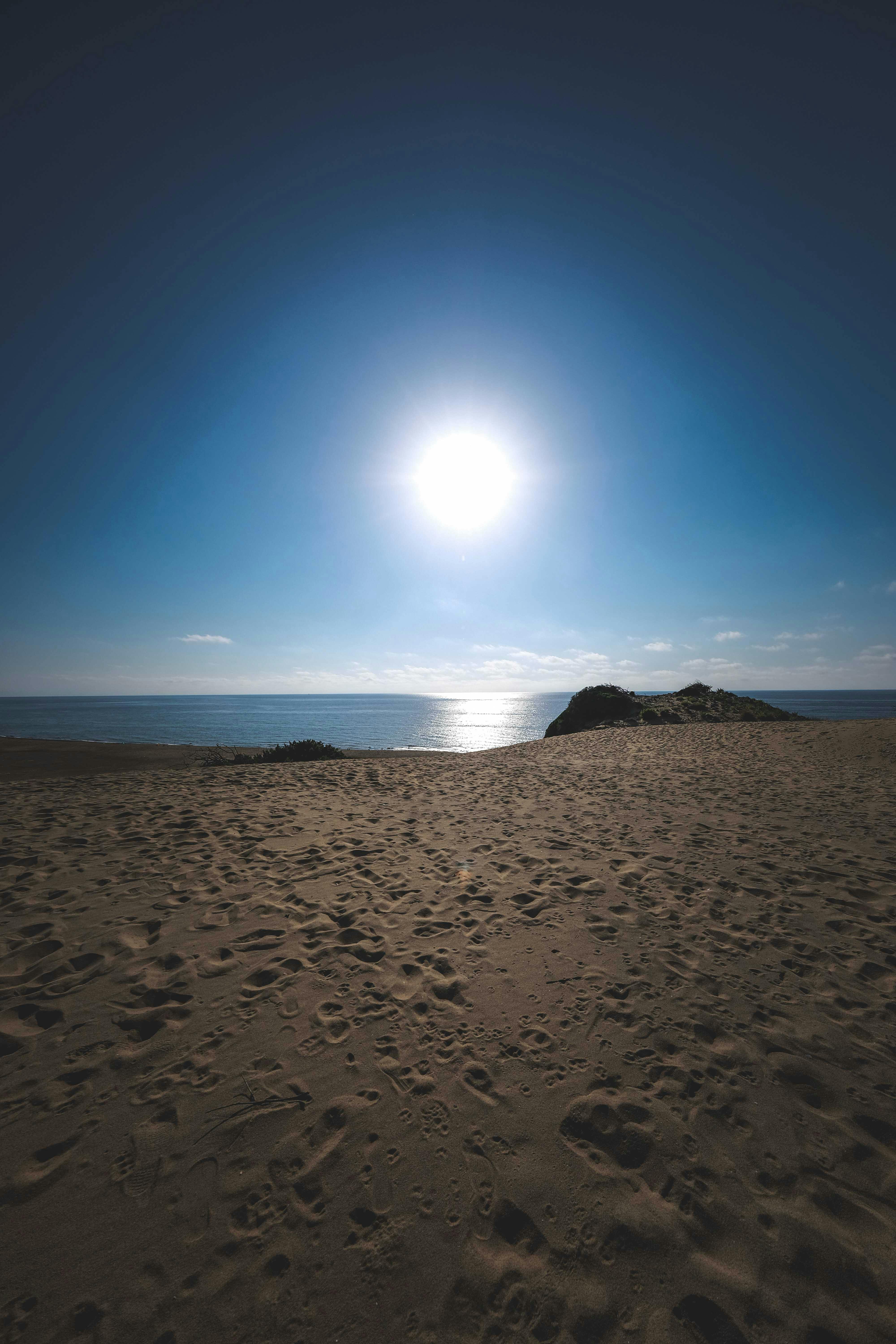 Sandy beach and sea under glowing sun in morning · Free Stock Photo