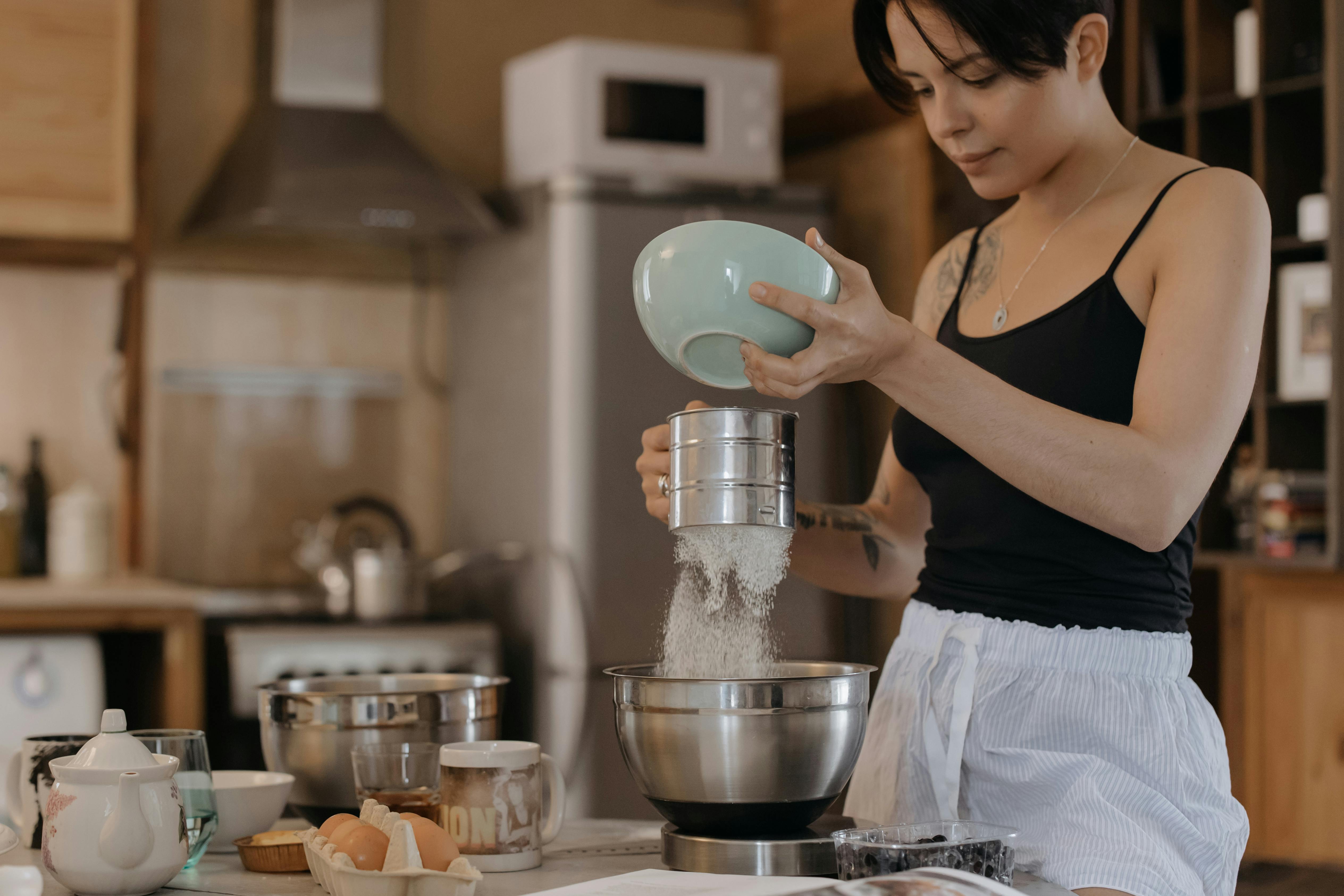 A Woman Sprinkling Flour on the Stainless Bowl · Free Stock Photo