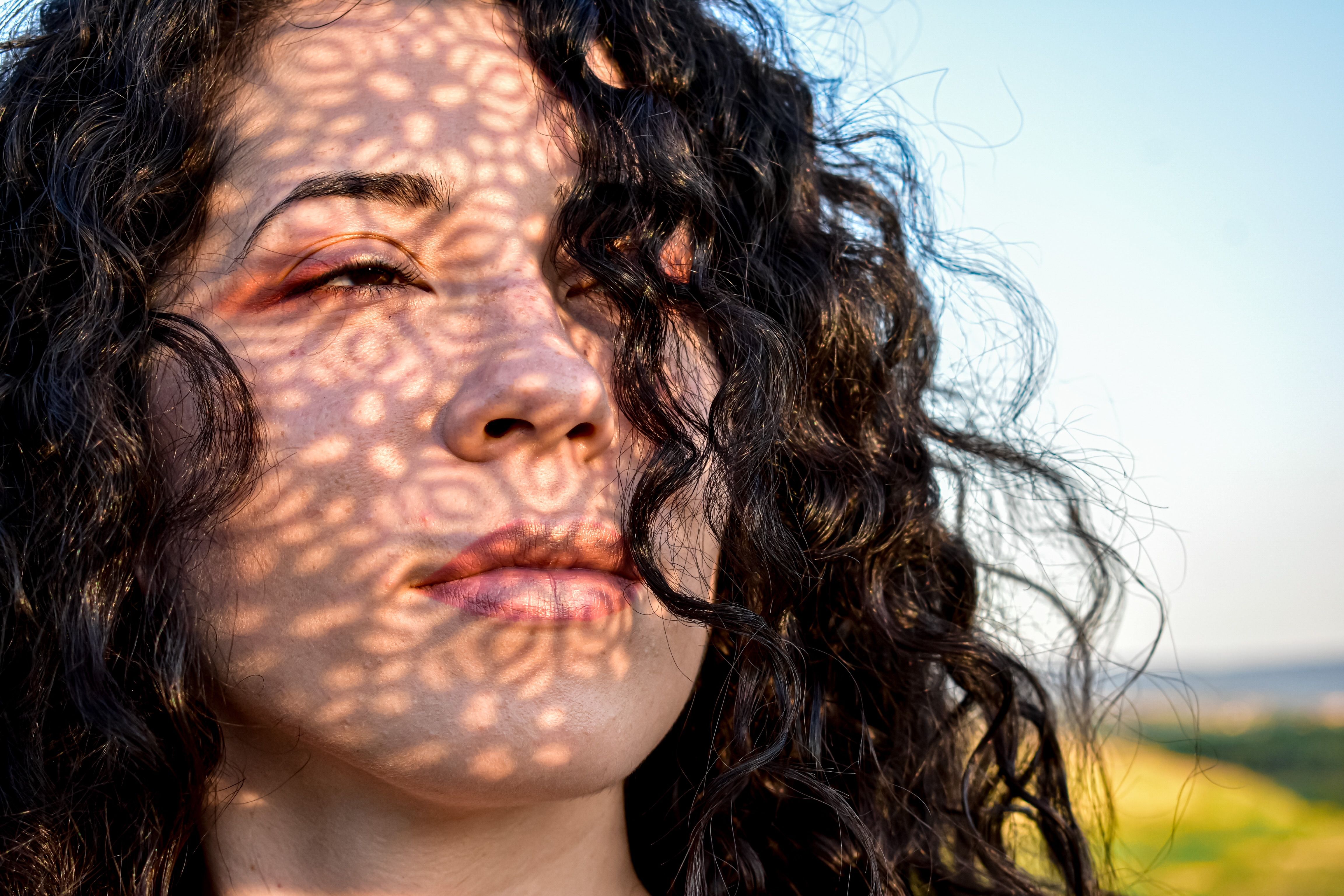 Crop charming woman with shadows on face standing on meadow · Free ...
