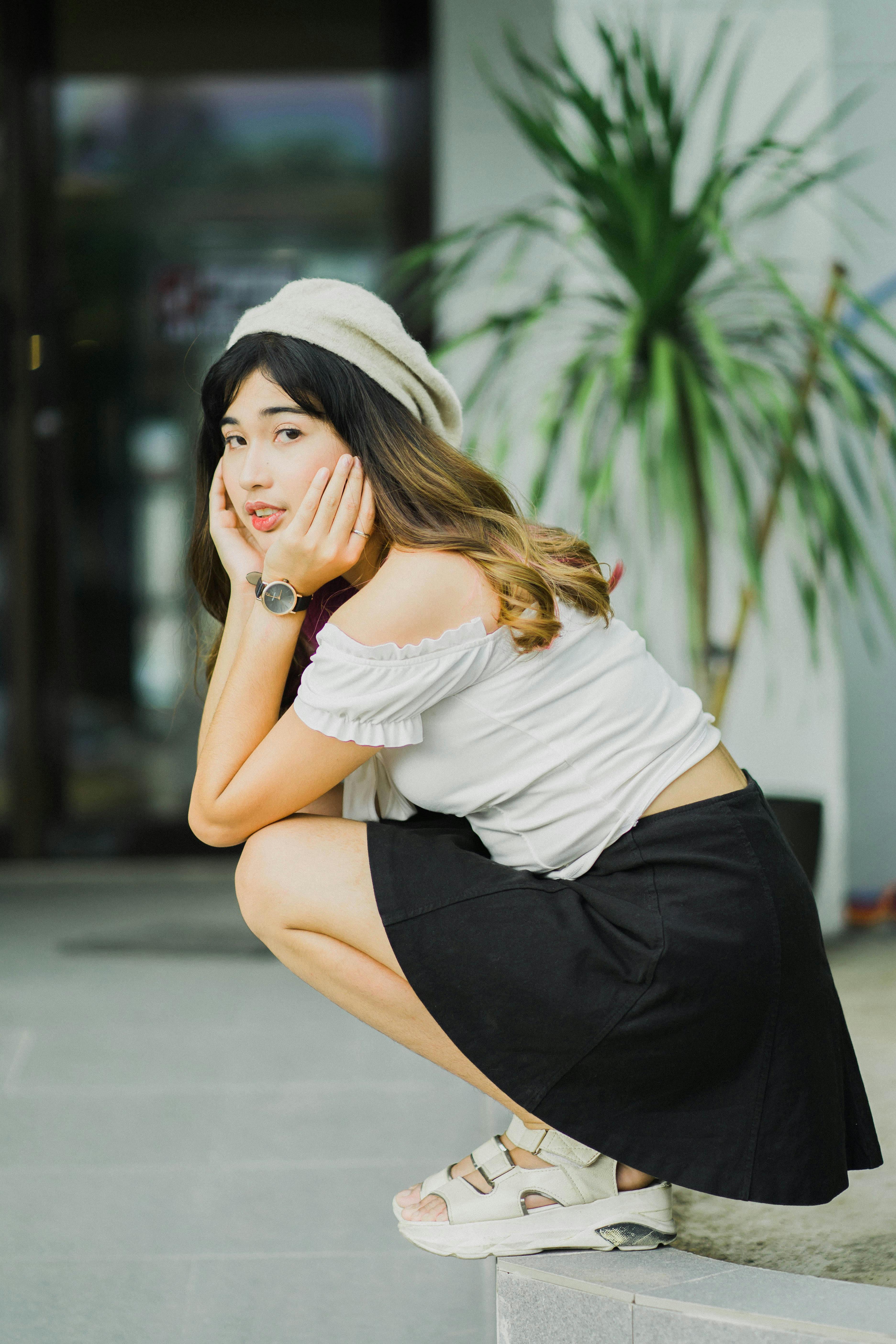 Trendy Asian woman sitting on haunches outside modern building · Free ...