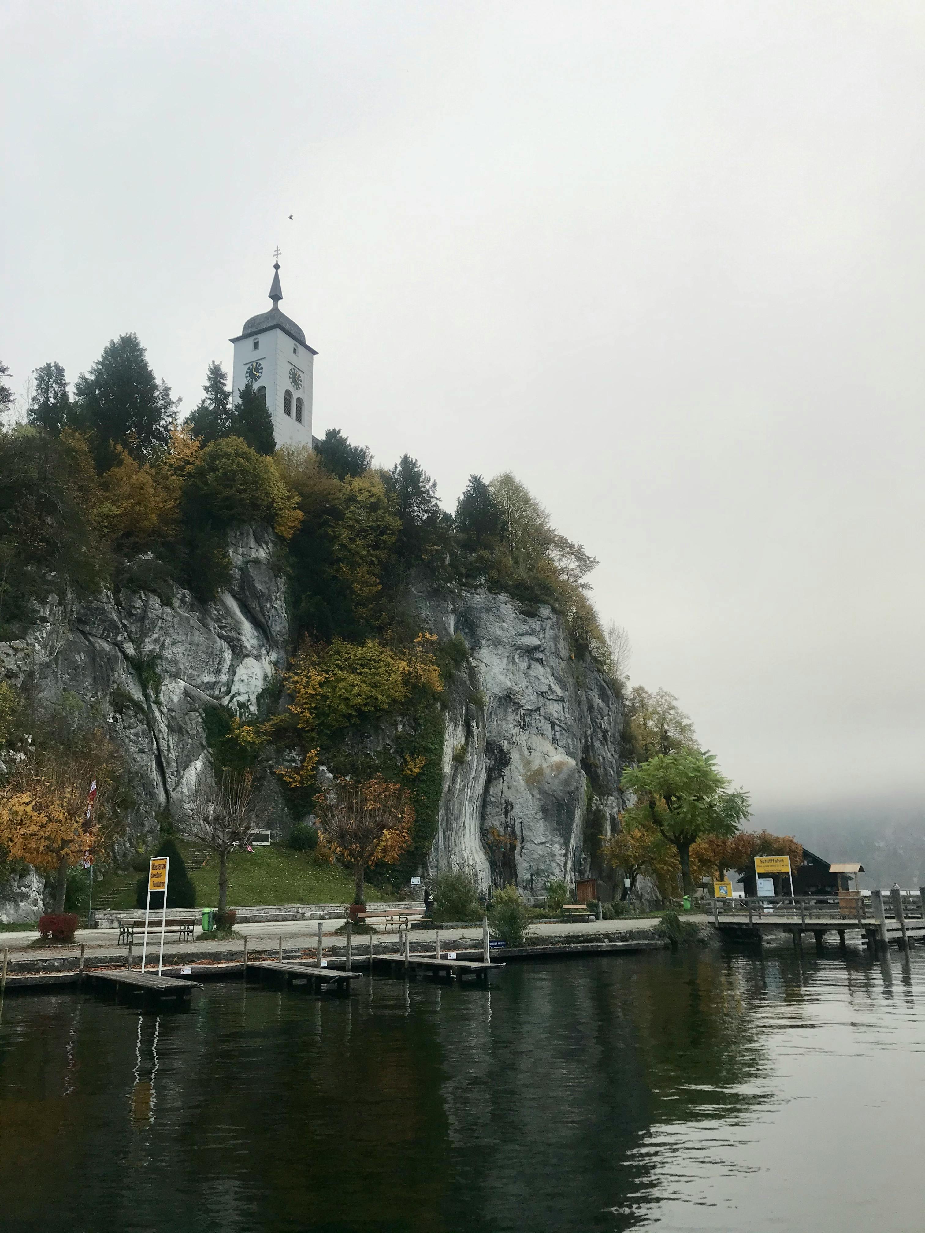 A Church on a Cliff with Lush Trees Near a Marina · Free Stock Photo