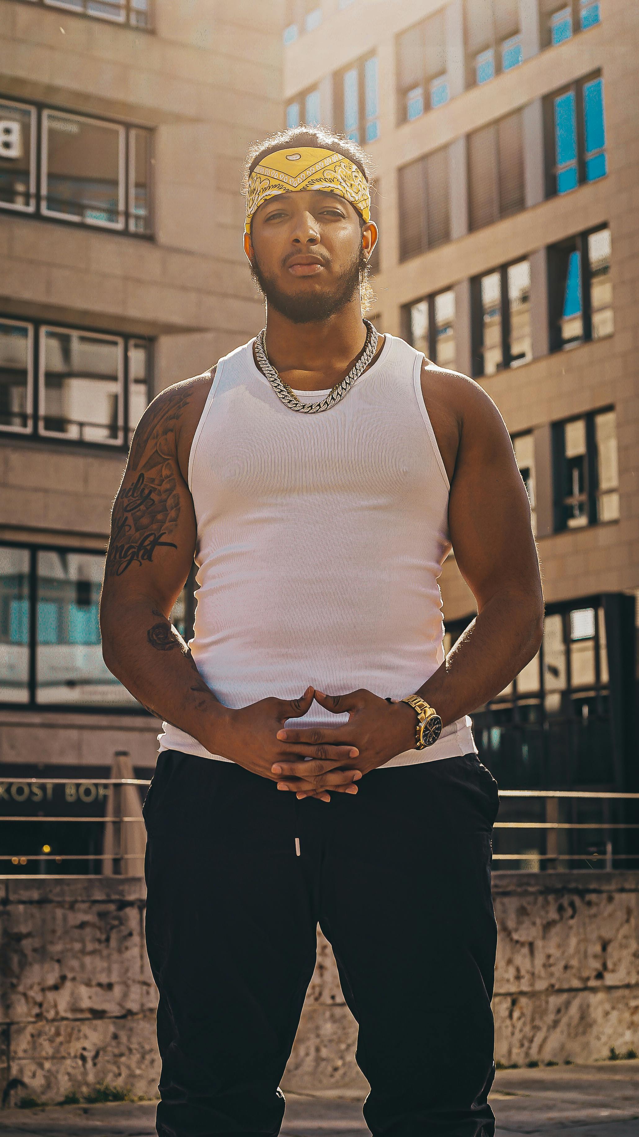Photo of a Cool Young Man Crouching on a Balcony · Free Stock Photo