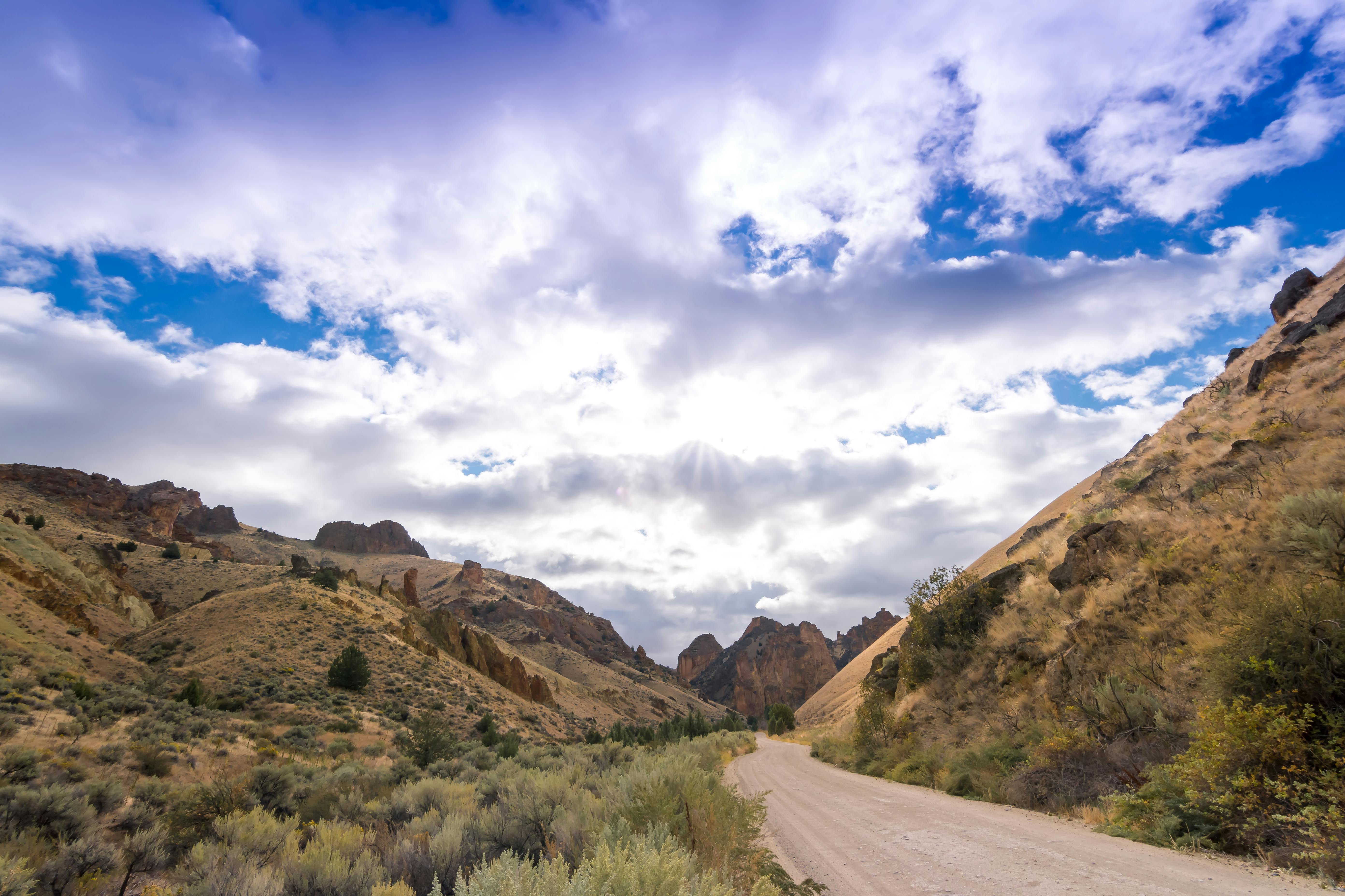 Empty sandy roadway in rocky terrain · Free Stock Photo