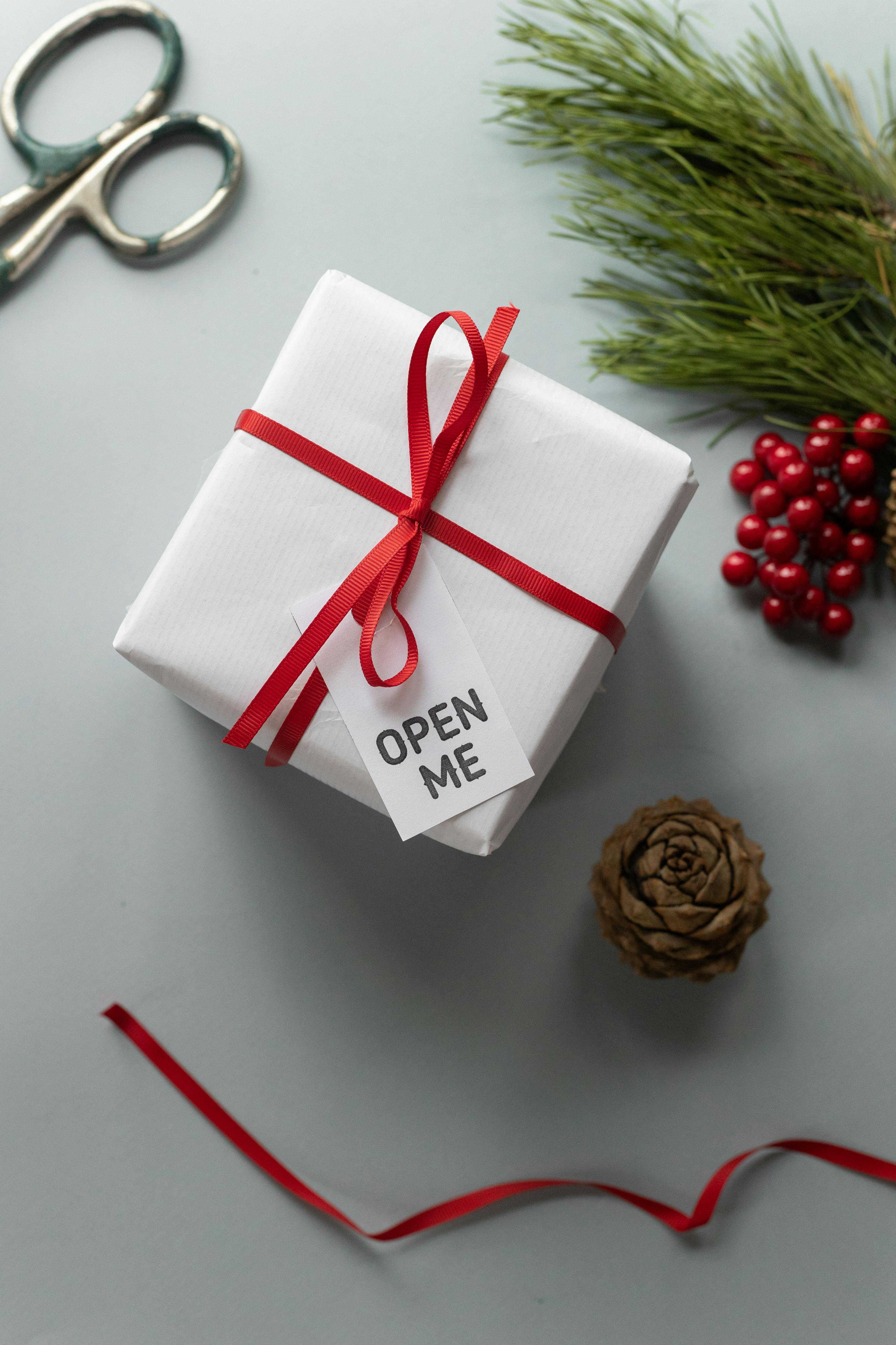 Open Me inscription on tag of present box near decor · Free Stock Photo