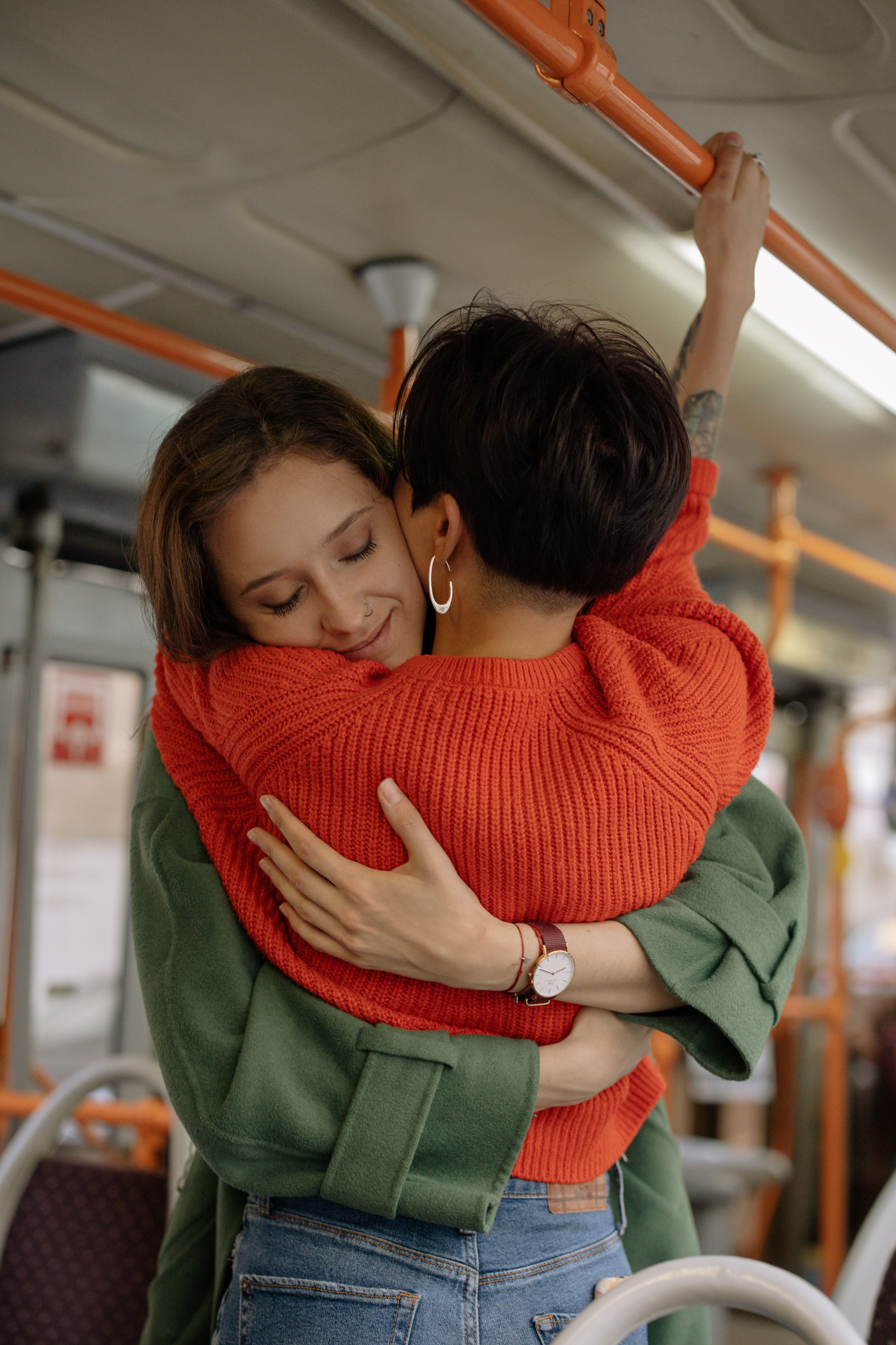 Woman in Red Sweater Hugging Woman in Green Jacket · Free Stock Photo