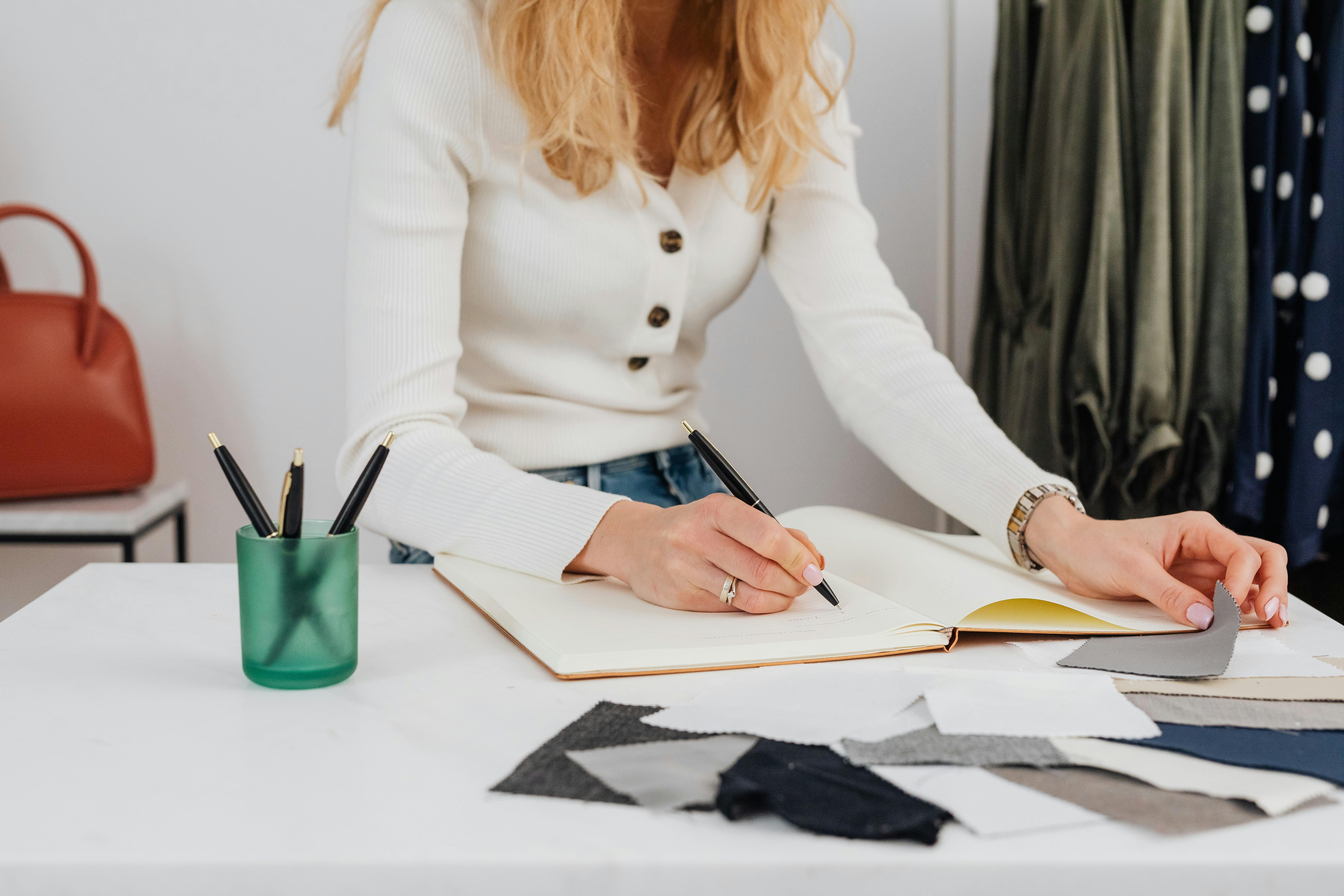 Woman in White Long Sleeves Writing on a Sketchpad · Free Stock Photo