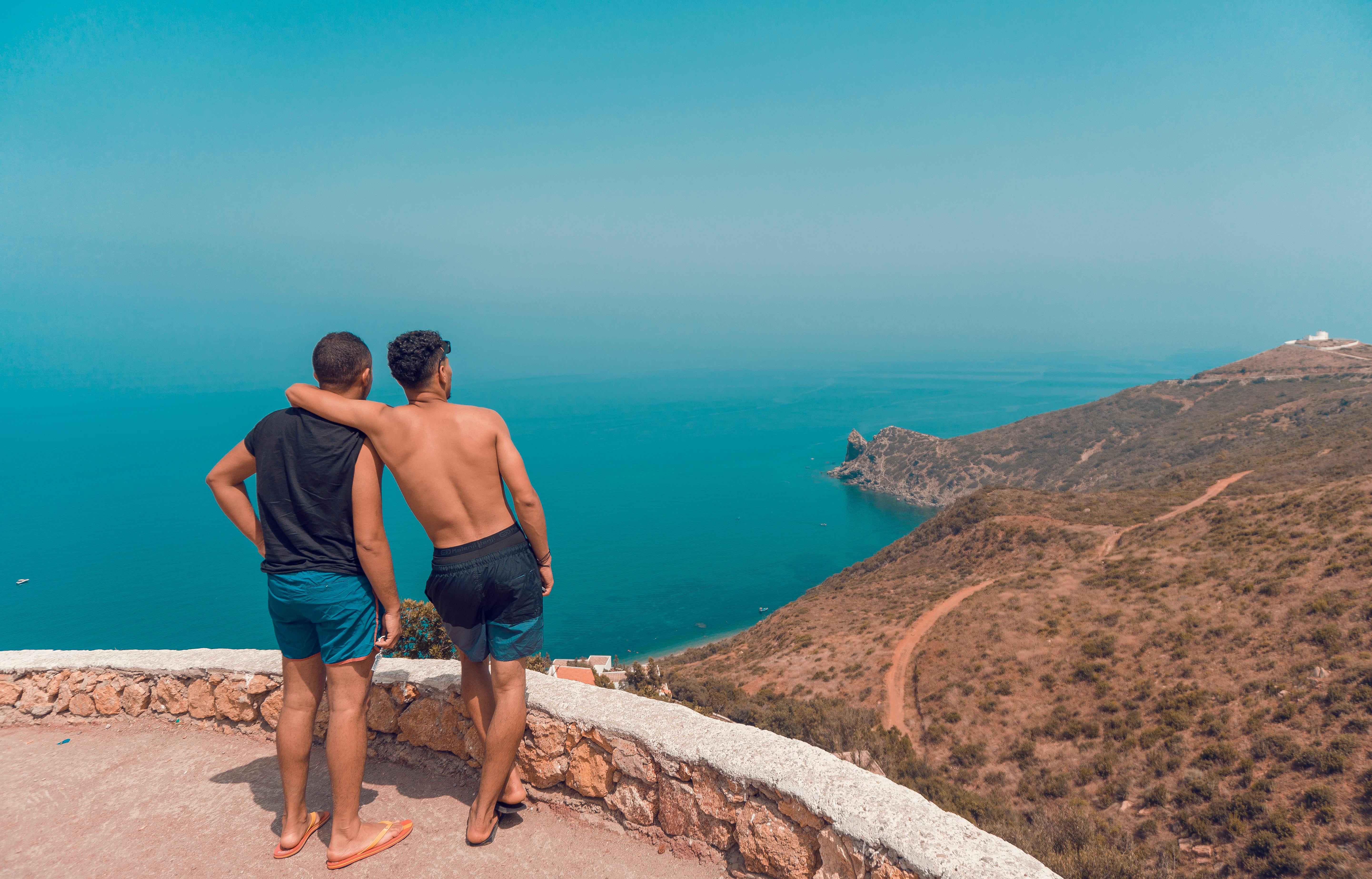 Two Man Standing on Mountain Cliff With Ocean View · Free Stock Photo