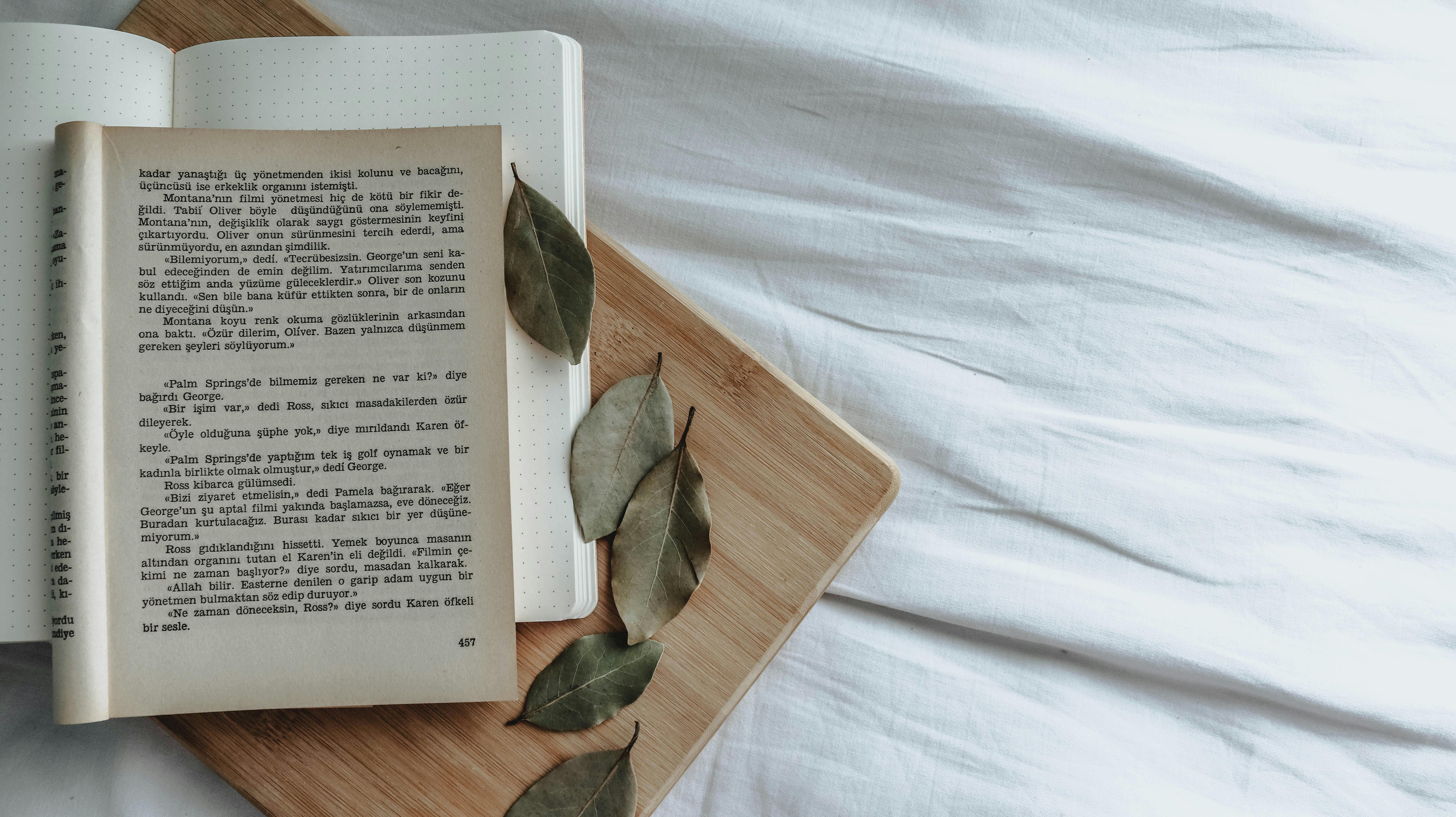 Open Book Lying on White Sheets · Free Stock Photo