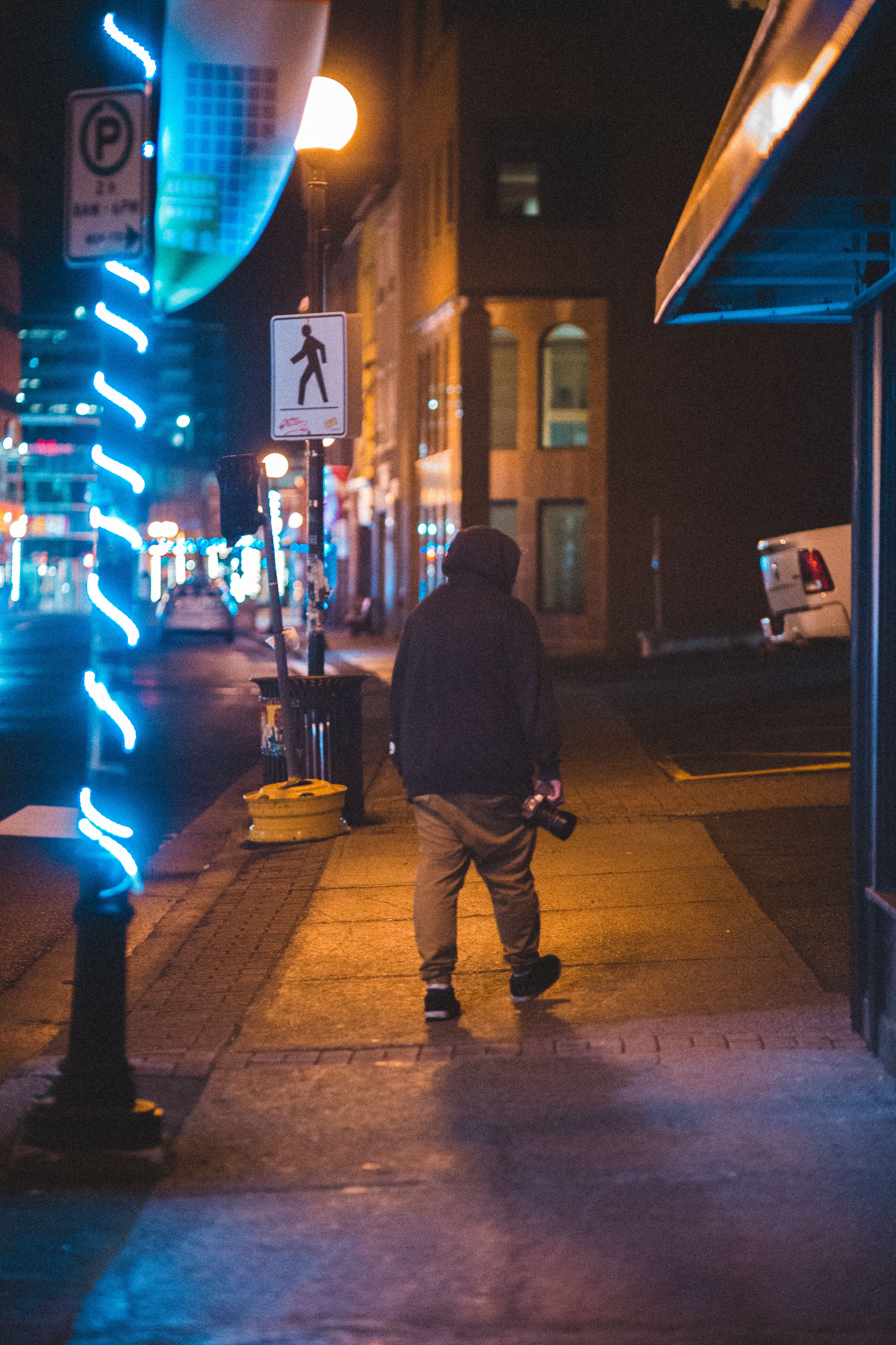 Man in hoodie walking on illuminated city street at night · Free Stock ...