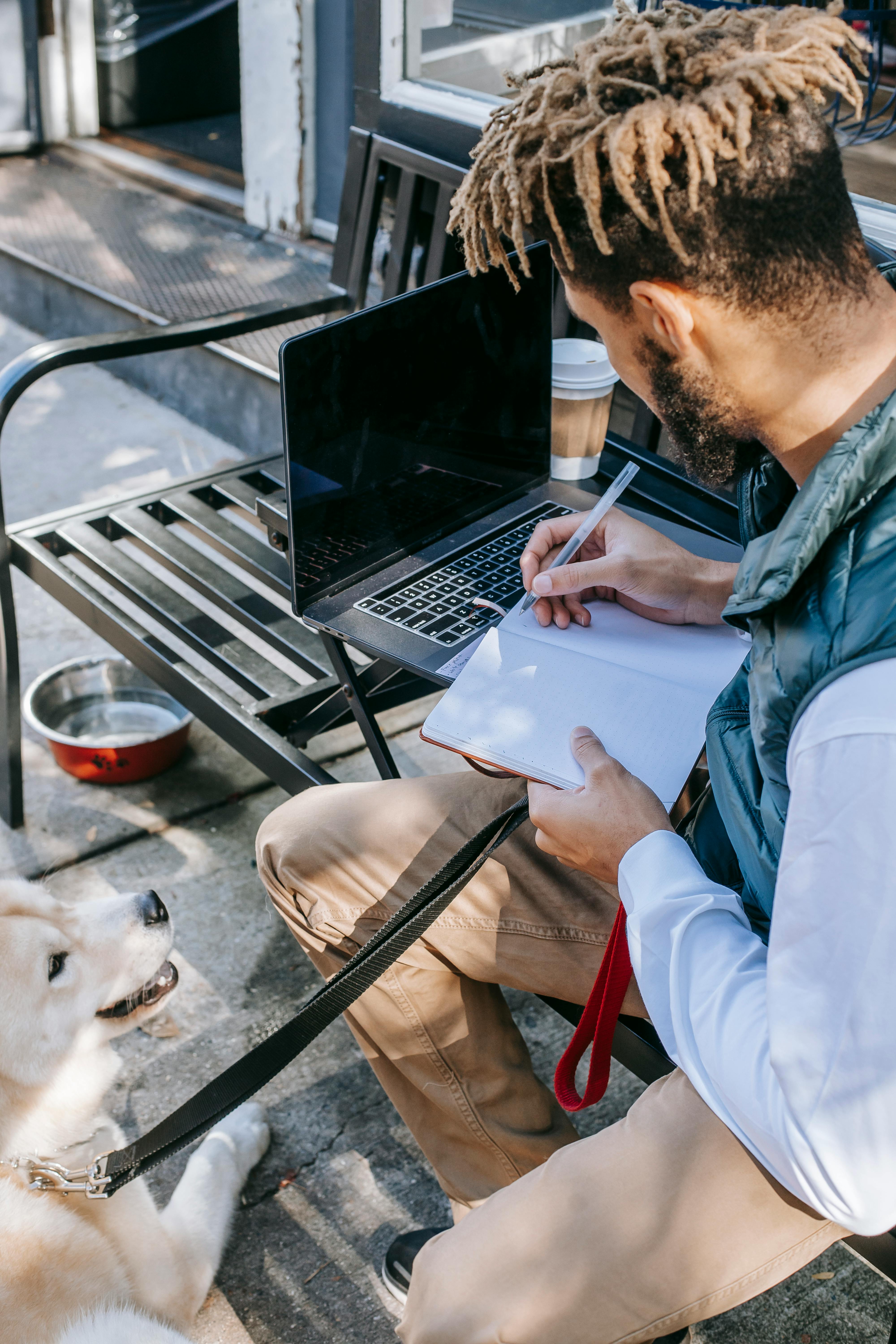 Black man with cute dog taking notes in notebook · Free Stock Photo