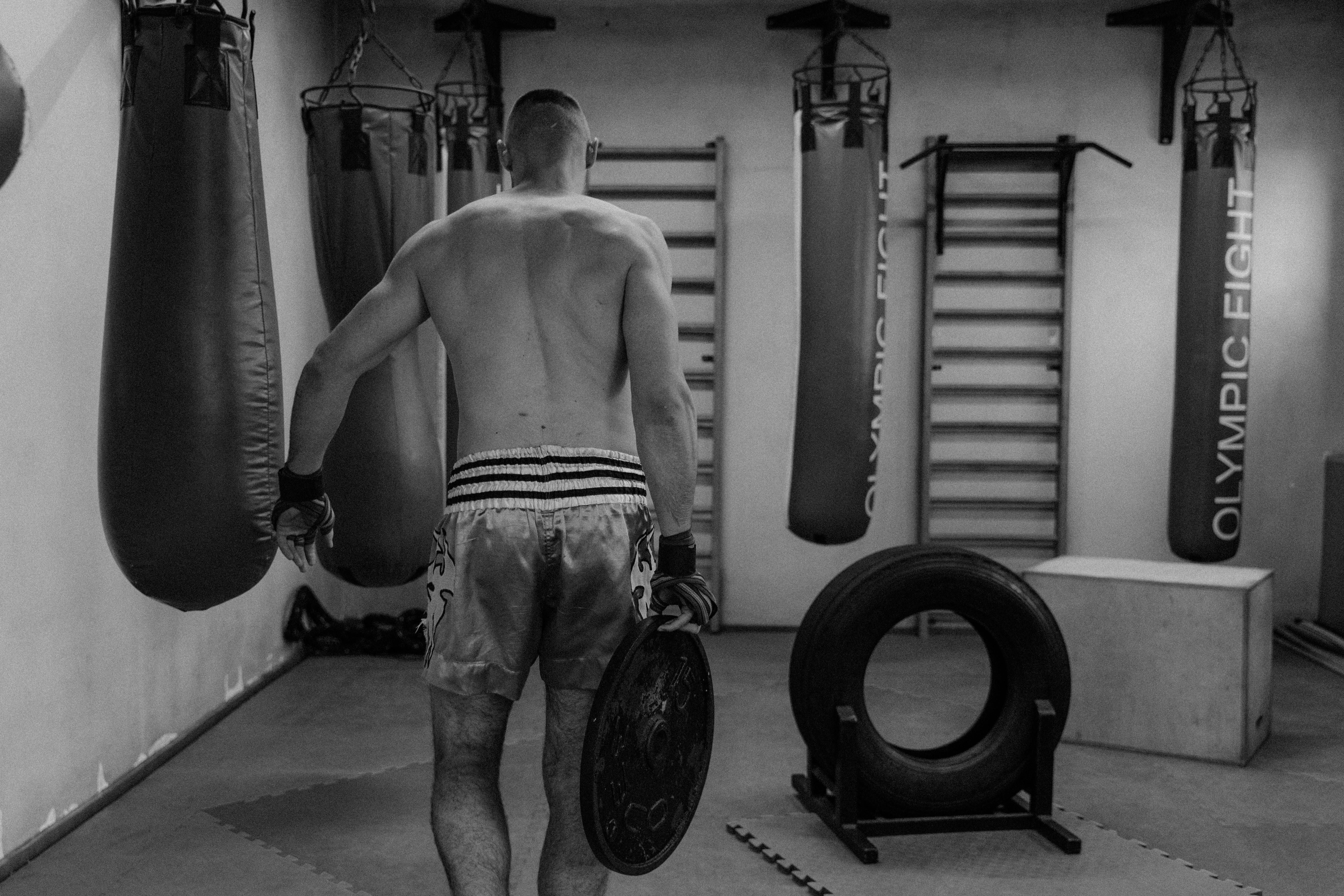 Shirtless Man Carrying a Weight Plate · Free Stock Photo
