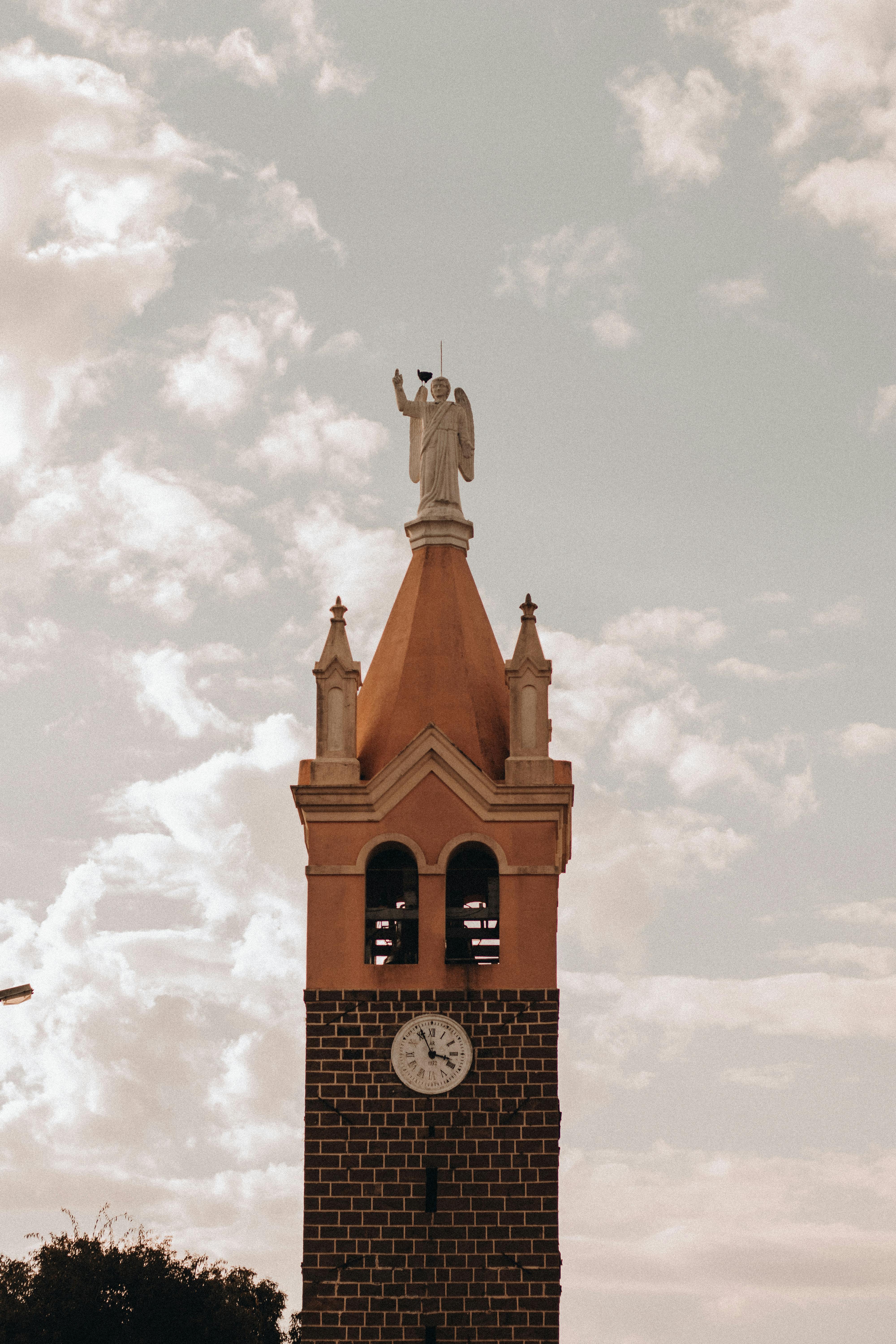 Brick clock tower with sculpture · Free Stock Photo
