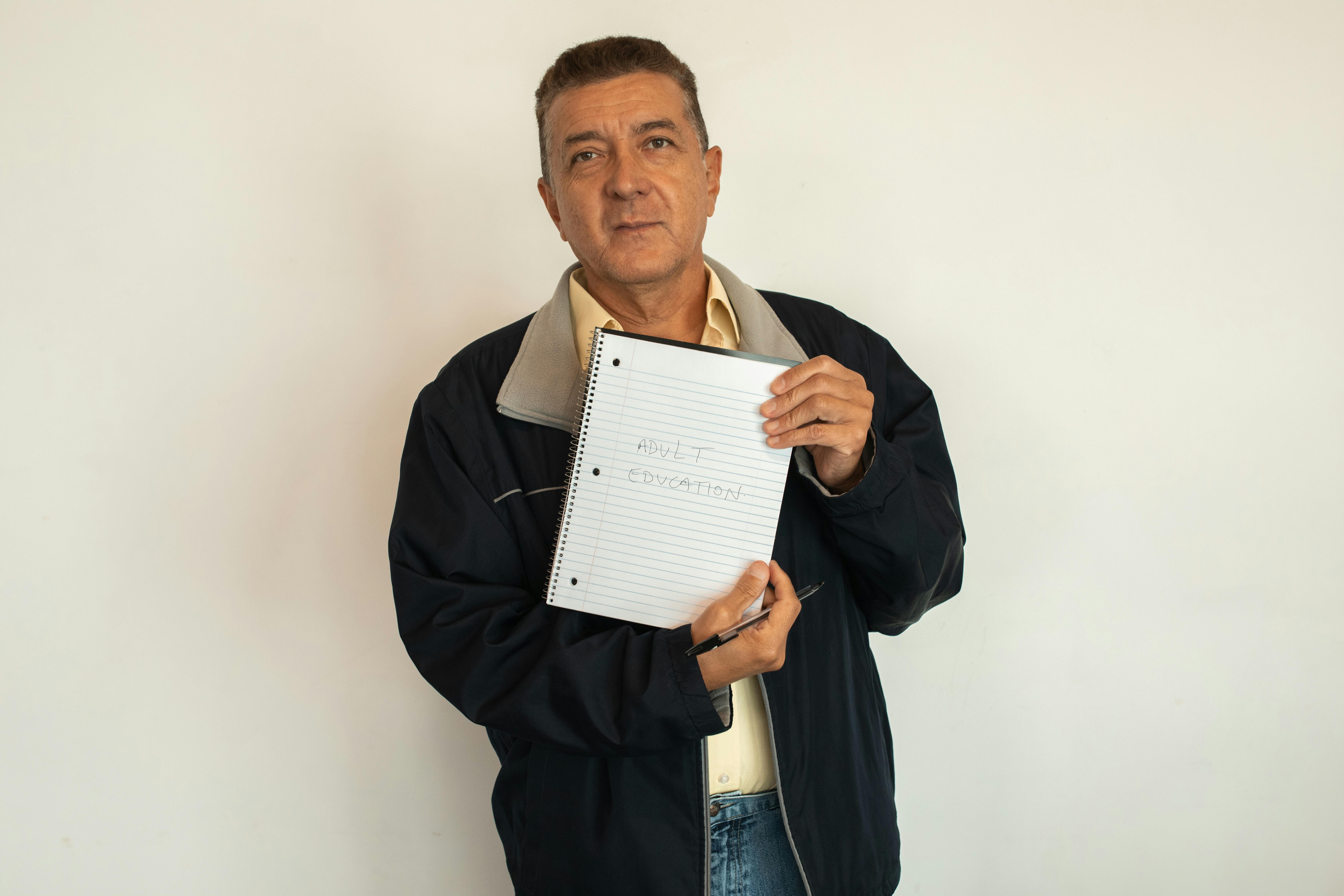 Man Wearing a Black Jacket Holding a Notebook · Free Stock Photo