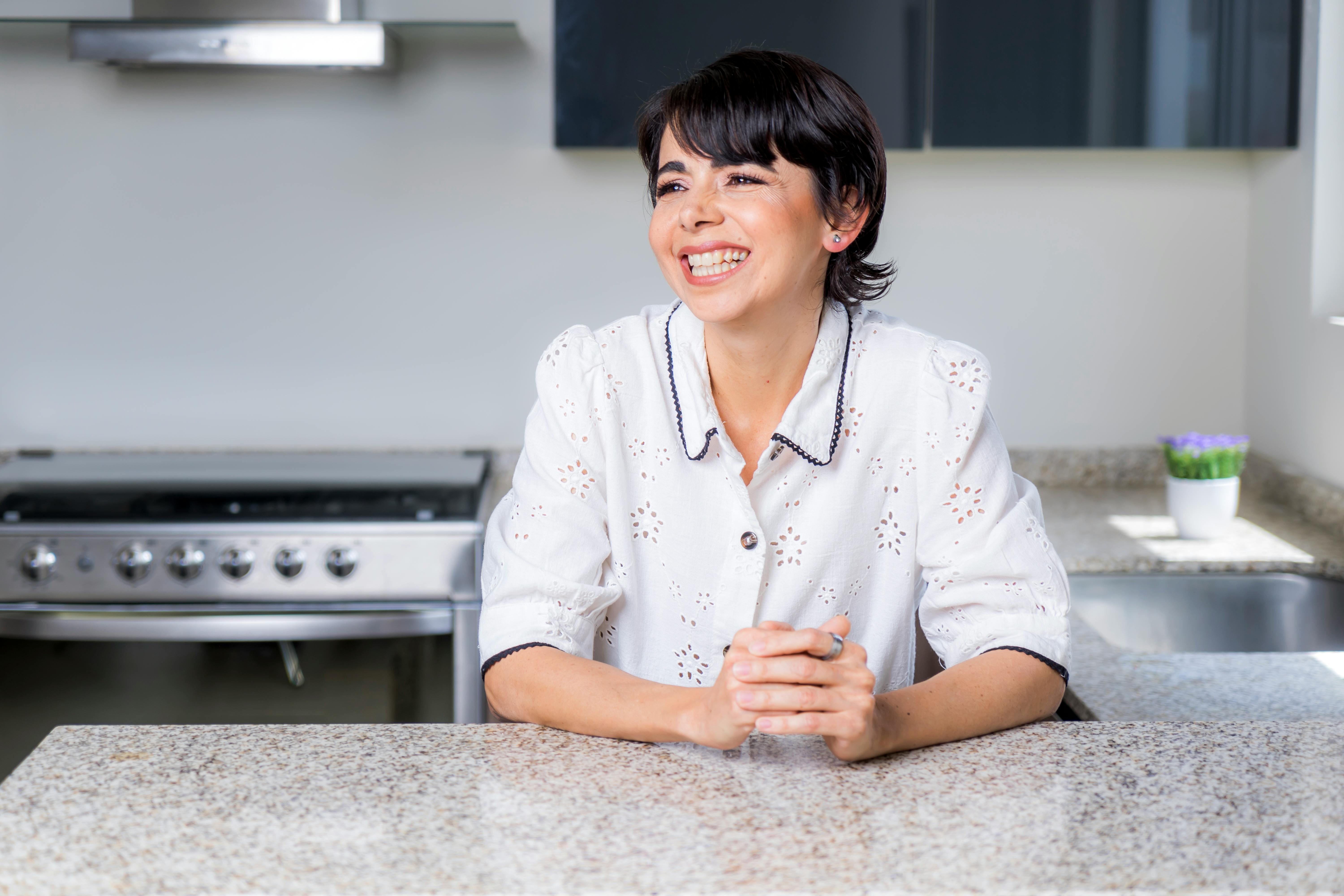 A Happy Woman Leaning on a Kitchen Counter Top · Free Stock Photo