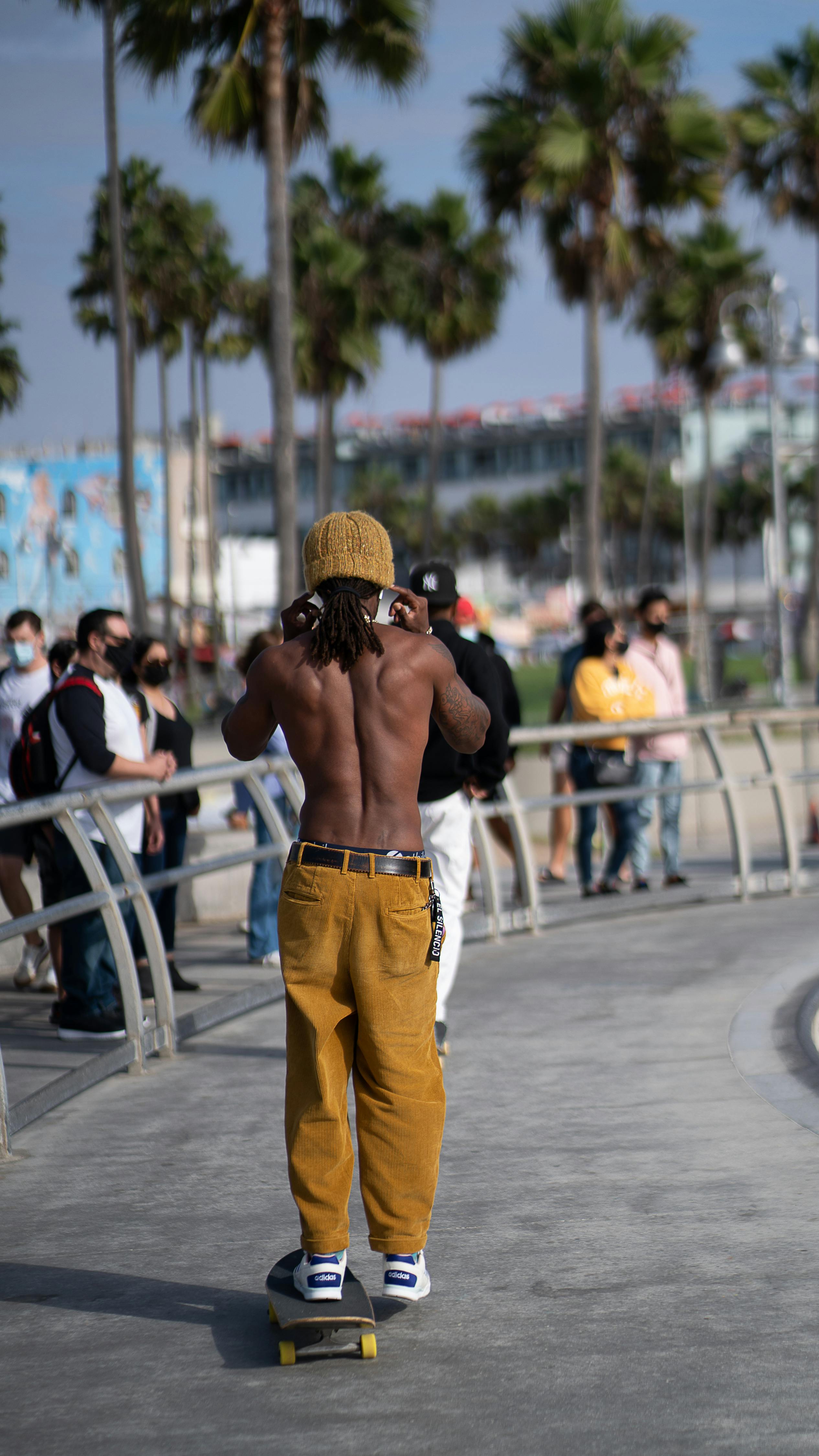 Black man without shirt riding skateboard along concrete road · Free ...