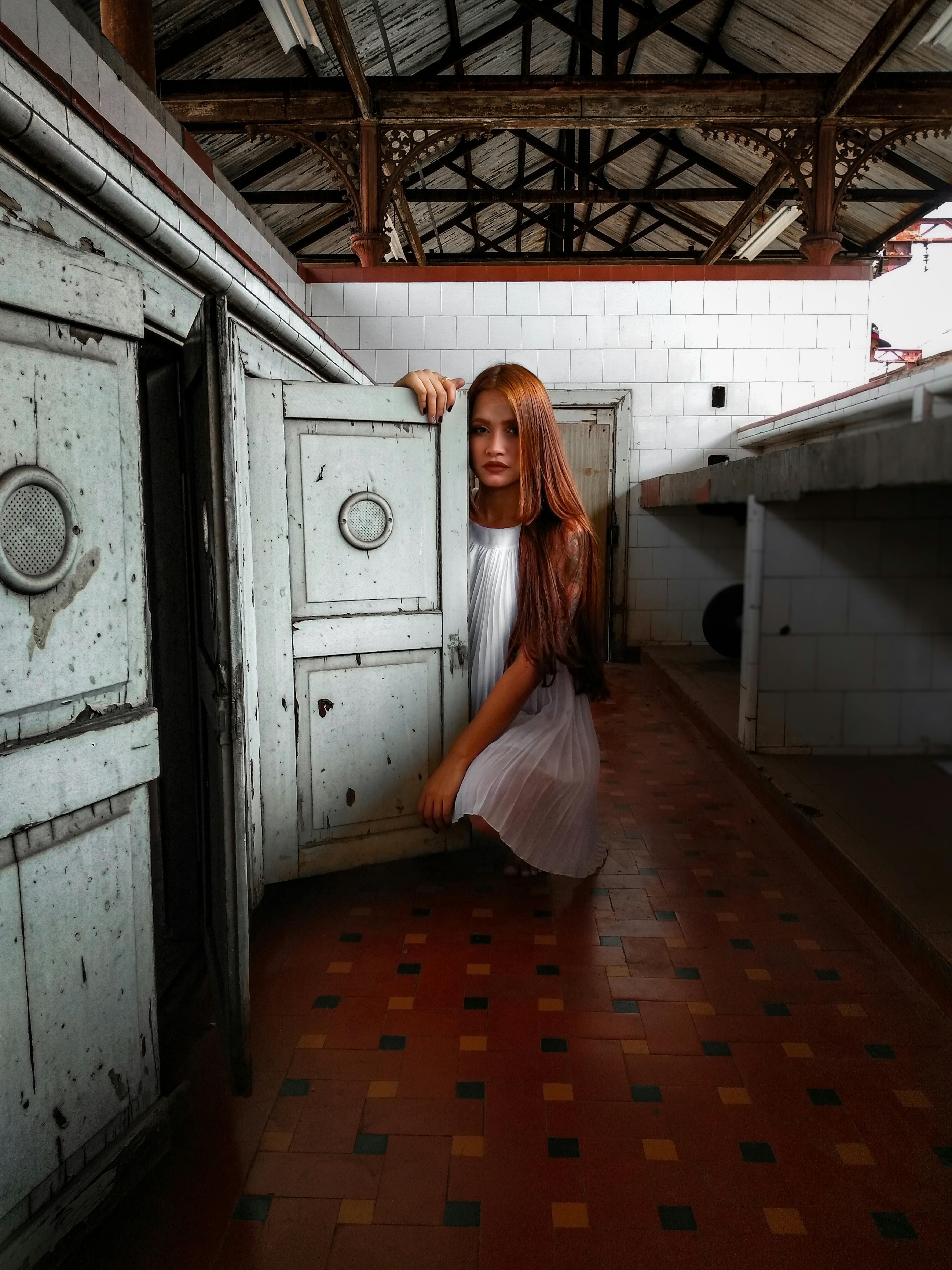 Stylish woman hunkering down near shabby cabinets · Free Stock Photo
