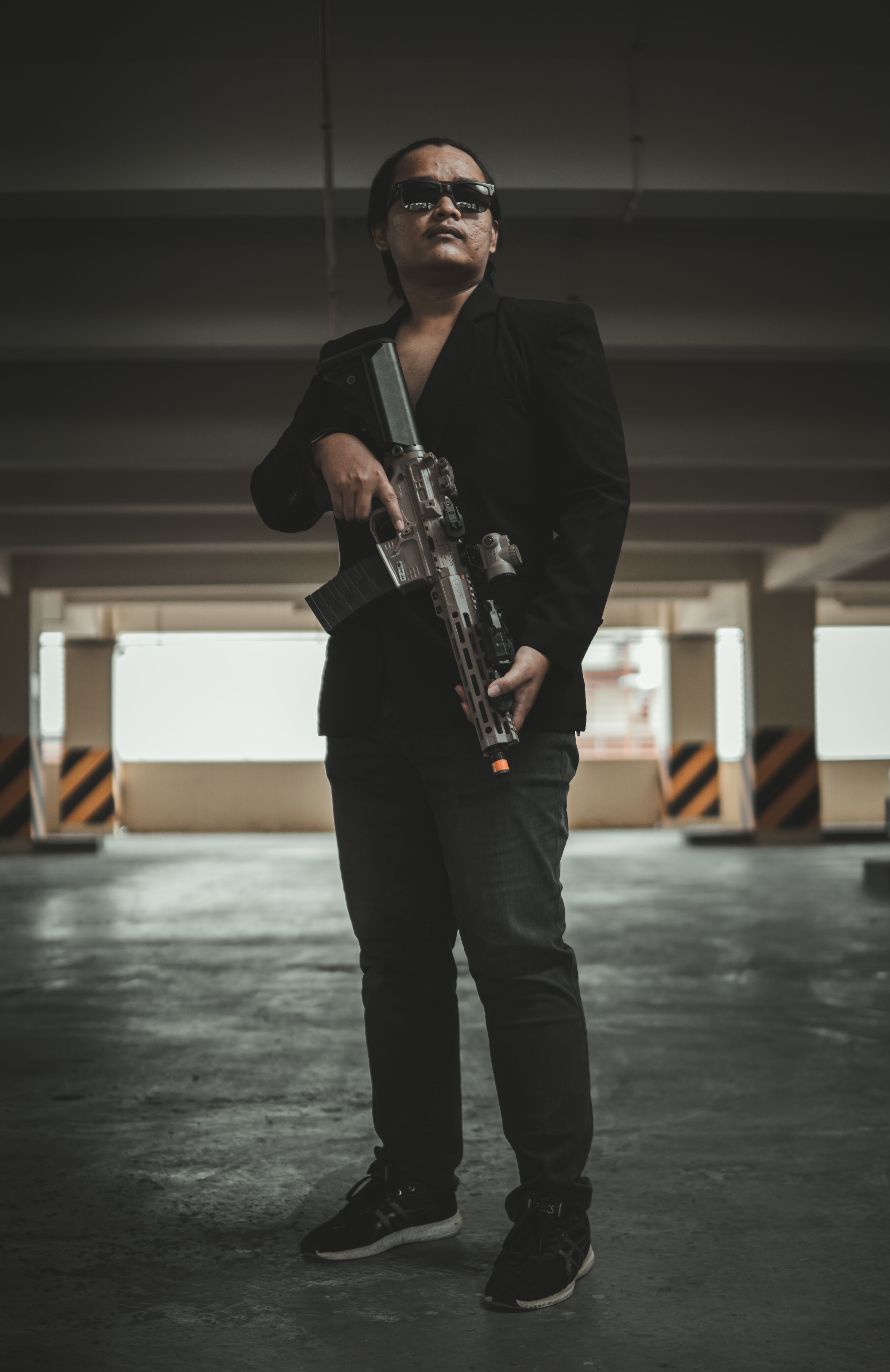 Low Angle View of a Man with Machine Gun in a Garage · Free Stock Photo
