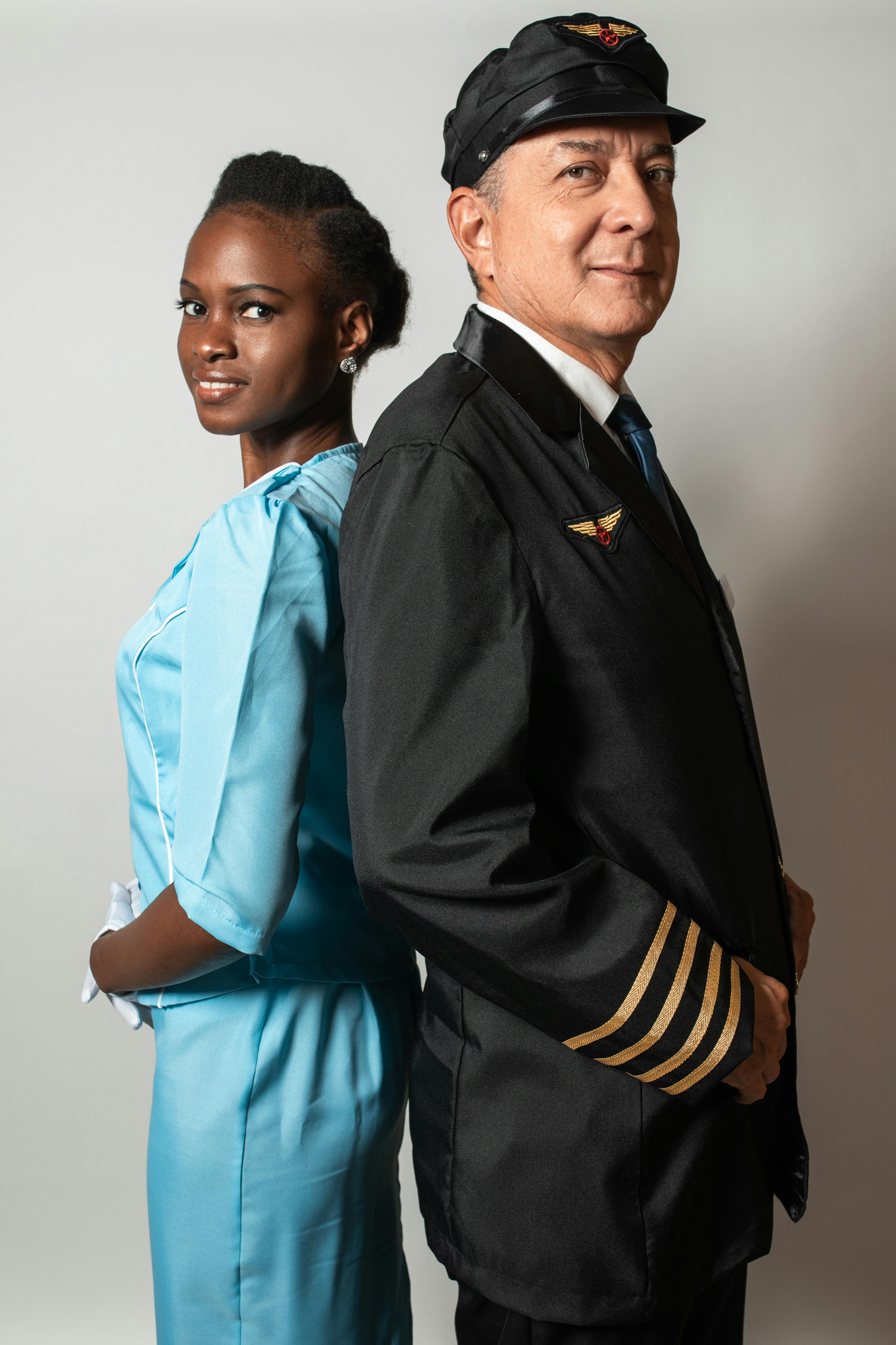 A Pilot and Stewardess Standing Back to Back · Free Stock Photo