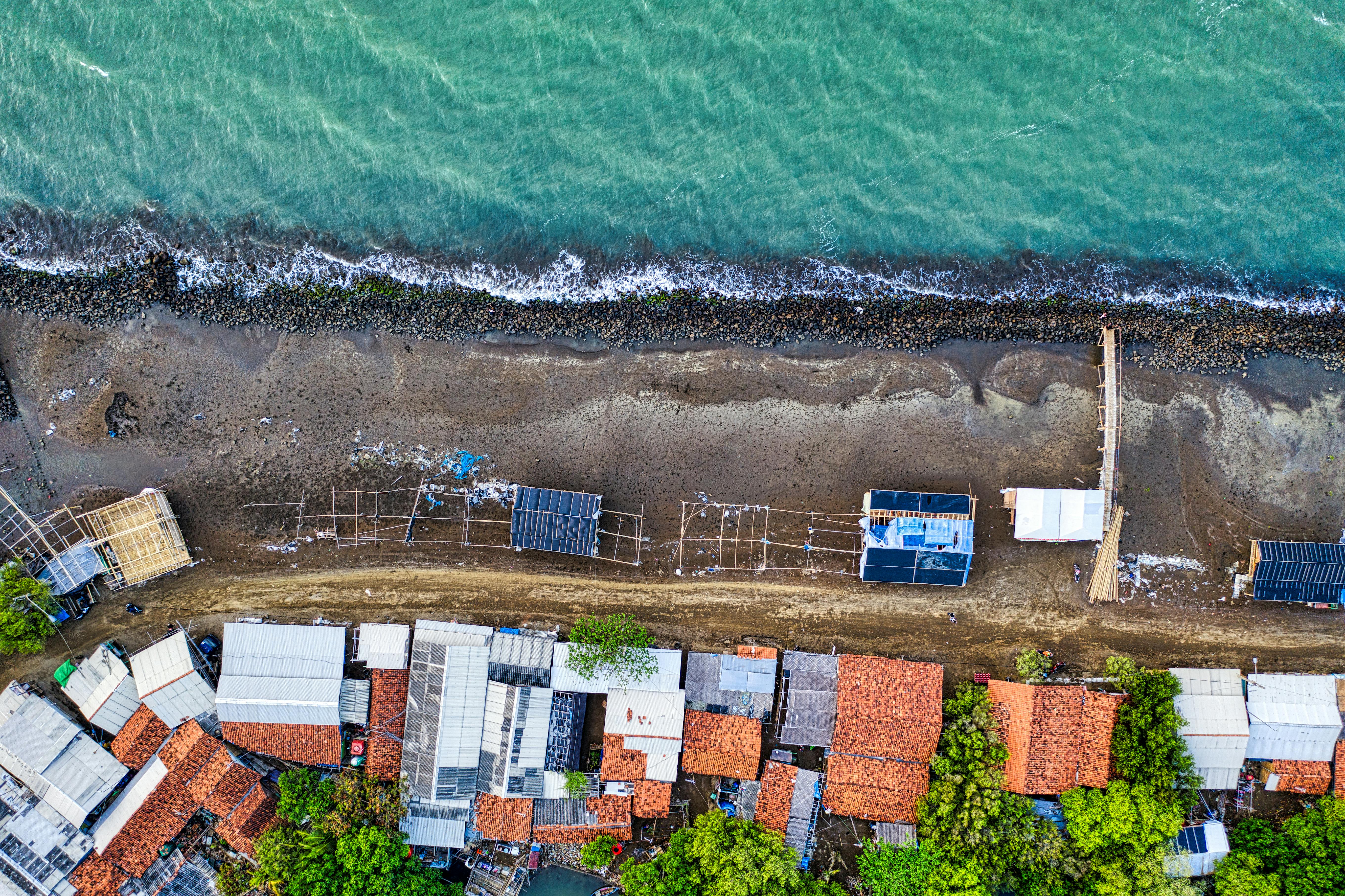 Building roofs on shore against rippled sea · Free Stock Photo