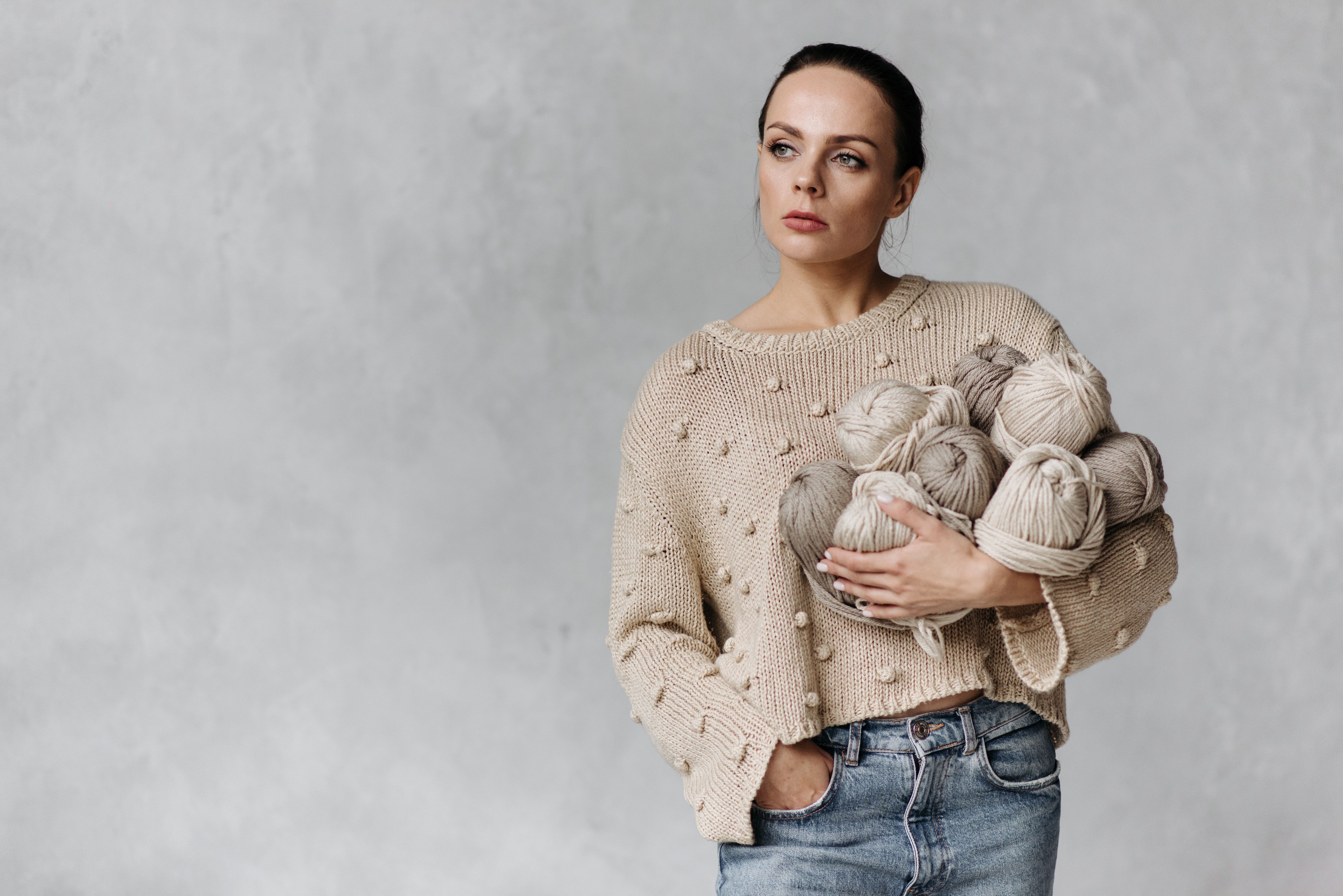 Woman in a Sweater Holding Yarns · Free Stock Photo
