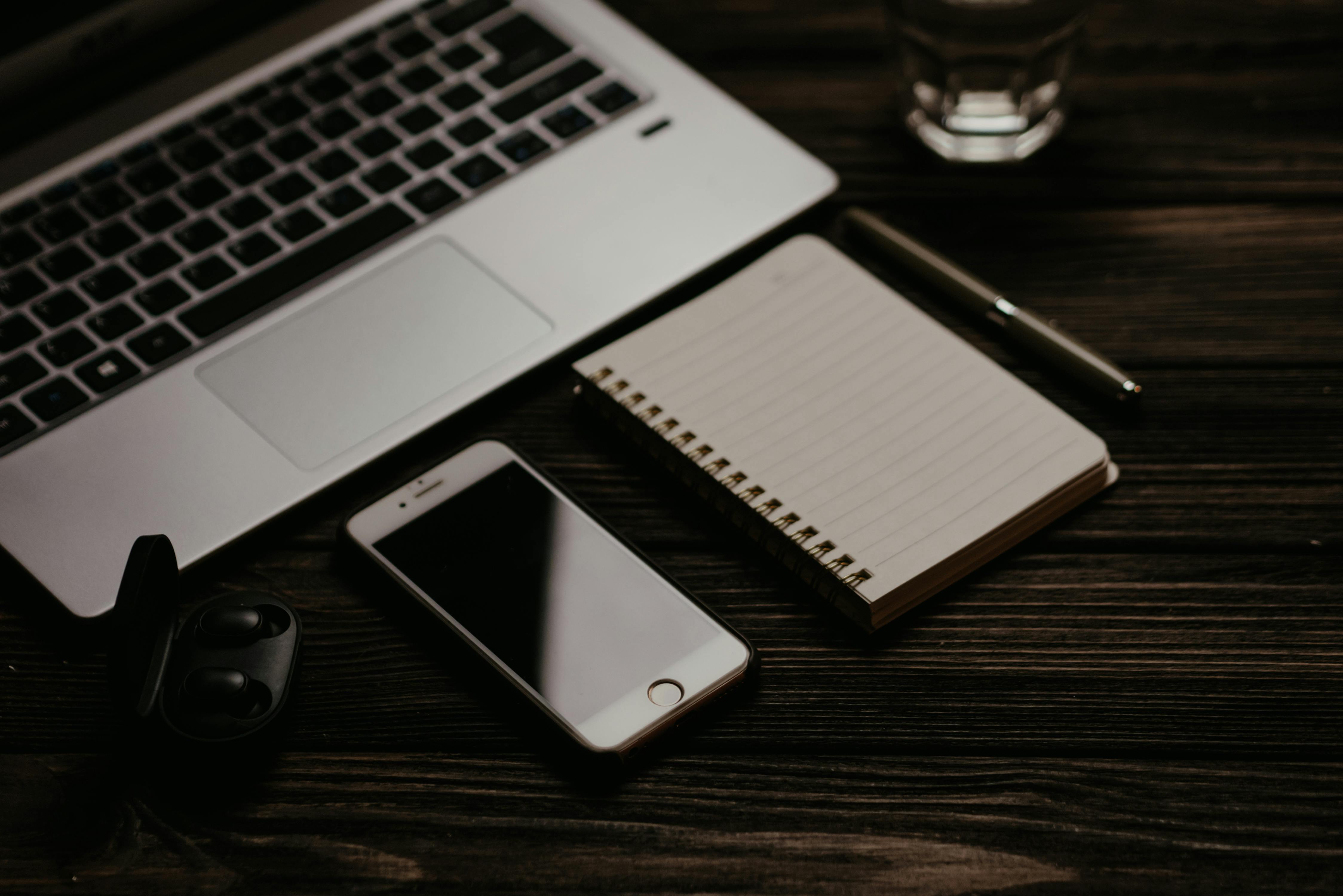 Iphone and Notepad near Laptop · Free Stock Photo