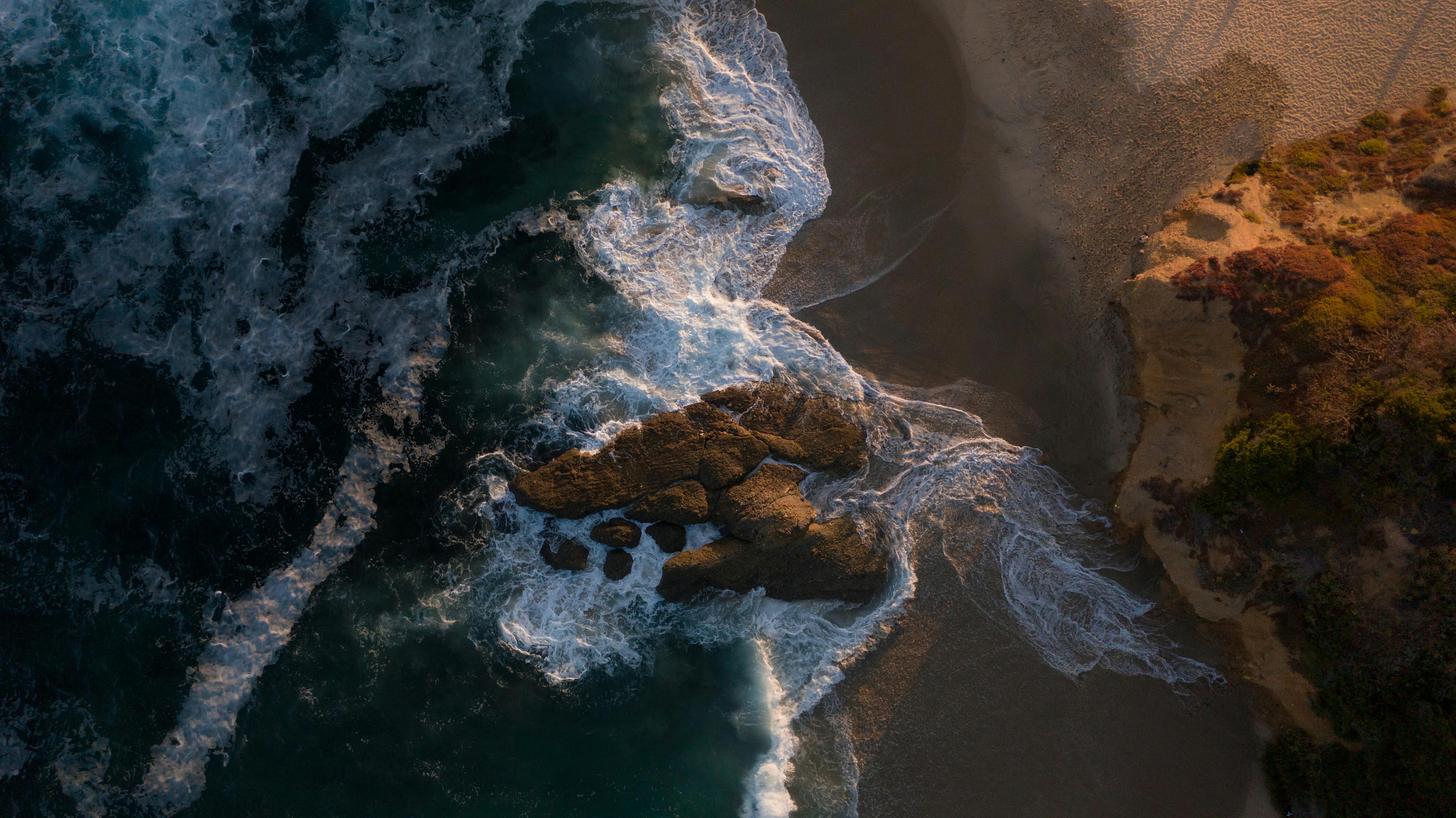 Aerial View of Waves Crashing the Shore with Rocks · Free Stock Photo