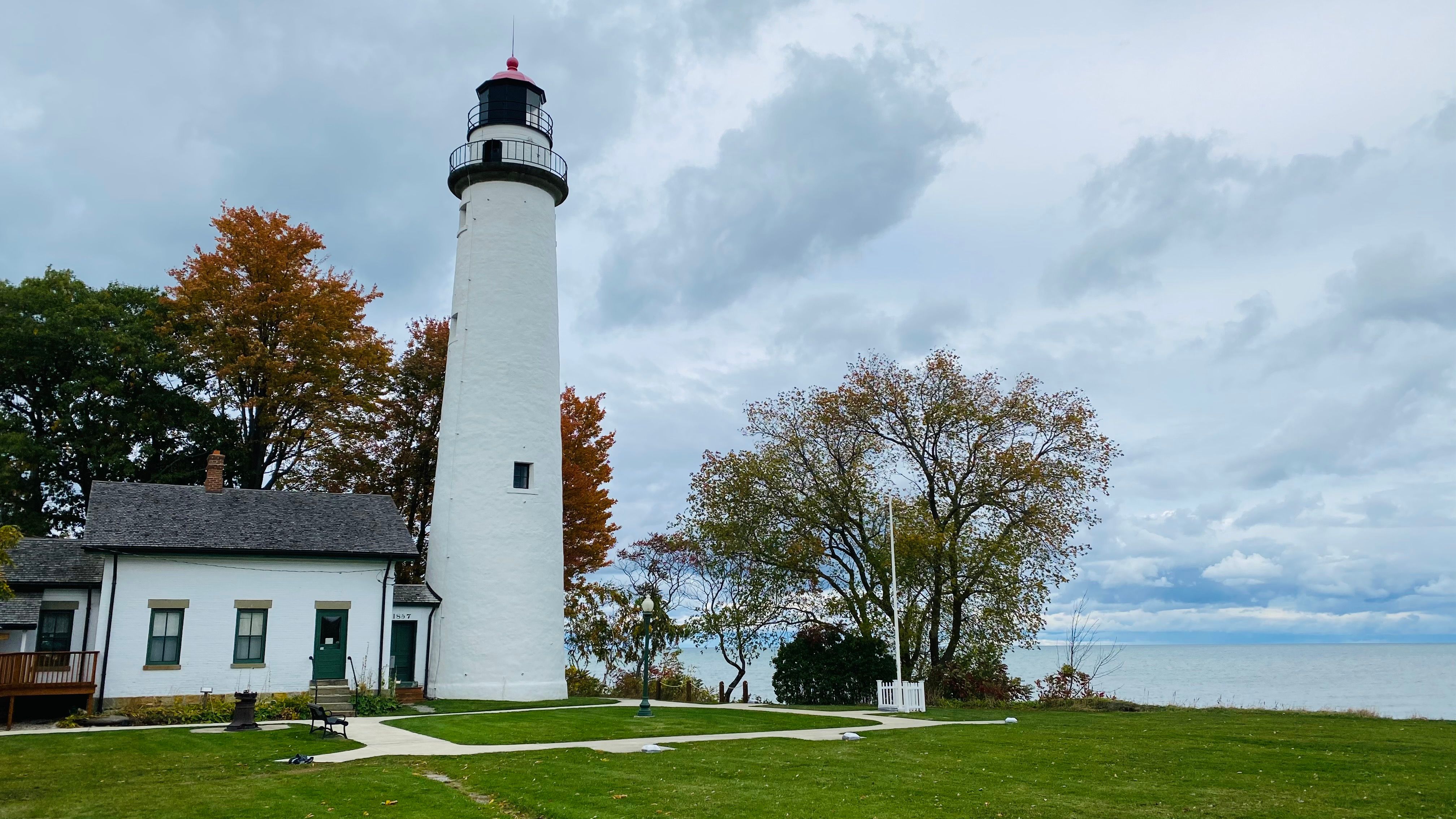 White Lighthouse Near Bungalow House · Free Stock Photo