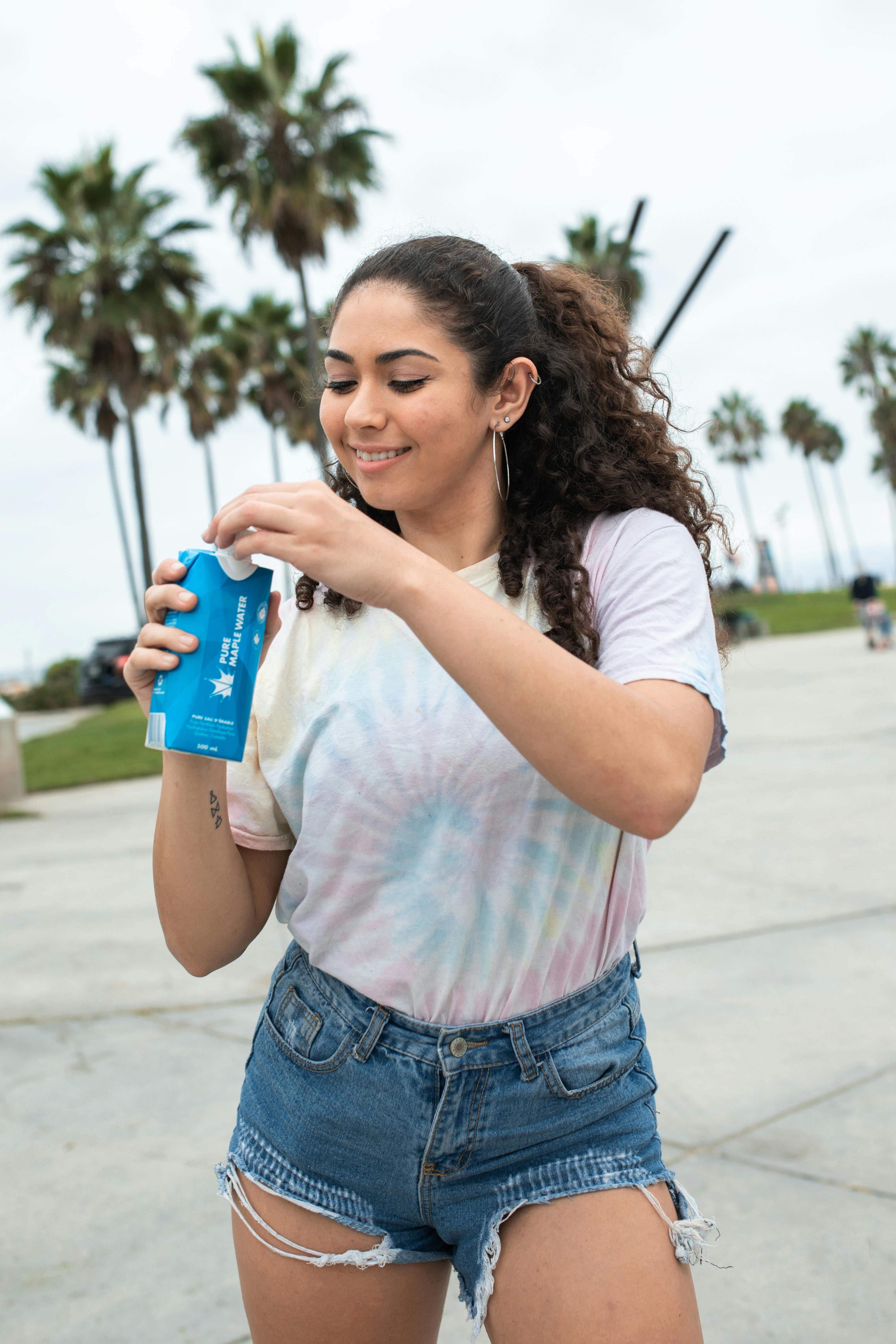 Woman in White T-shirt and Blue Denim Shorts Holding Blue Plastic Cup ...