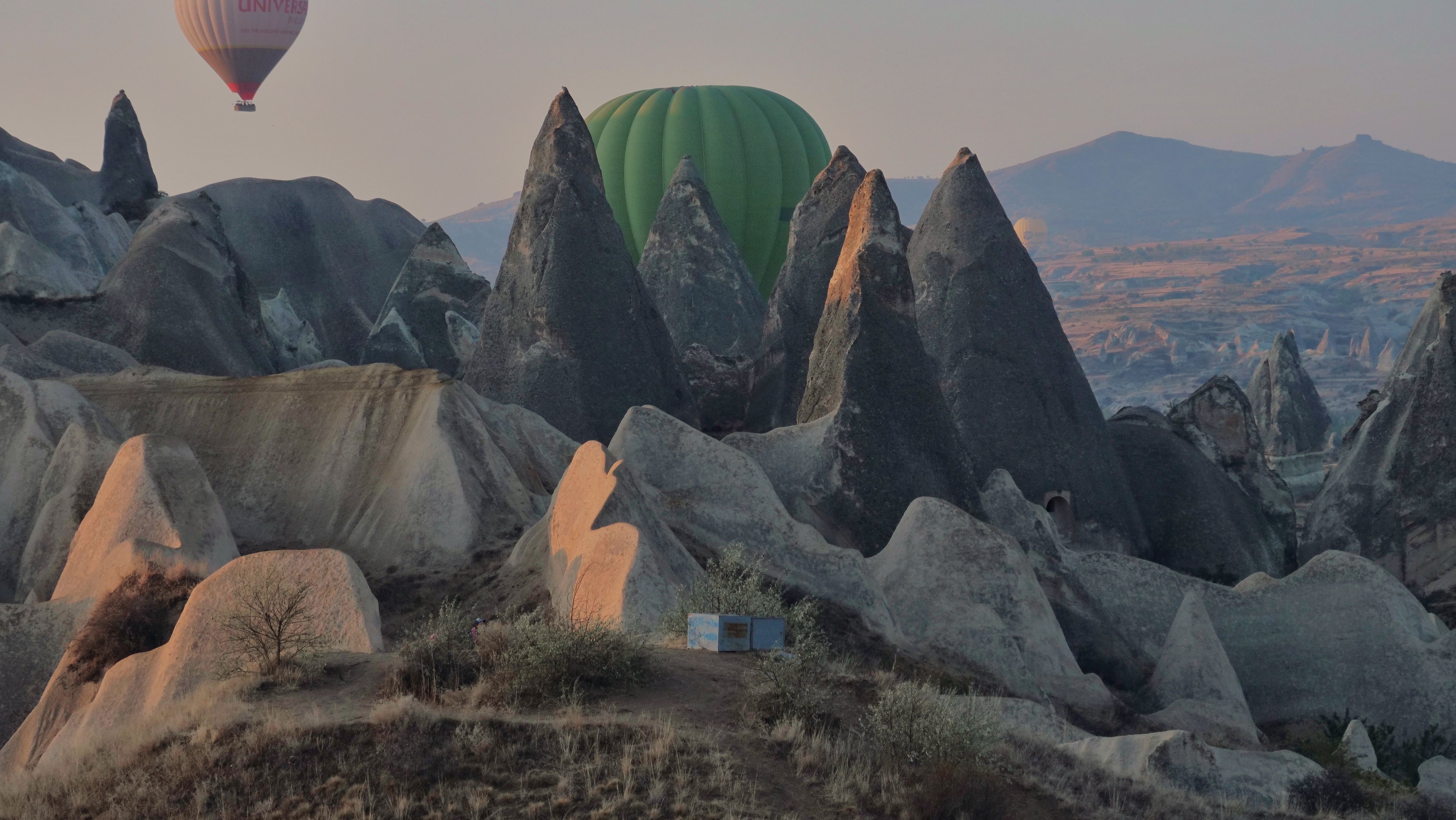 Green Hot Air Balloon Behind Natural Rock Formations · Free Stock Photo
