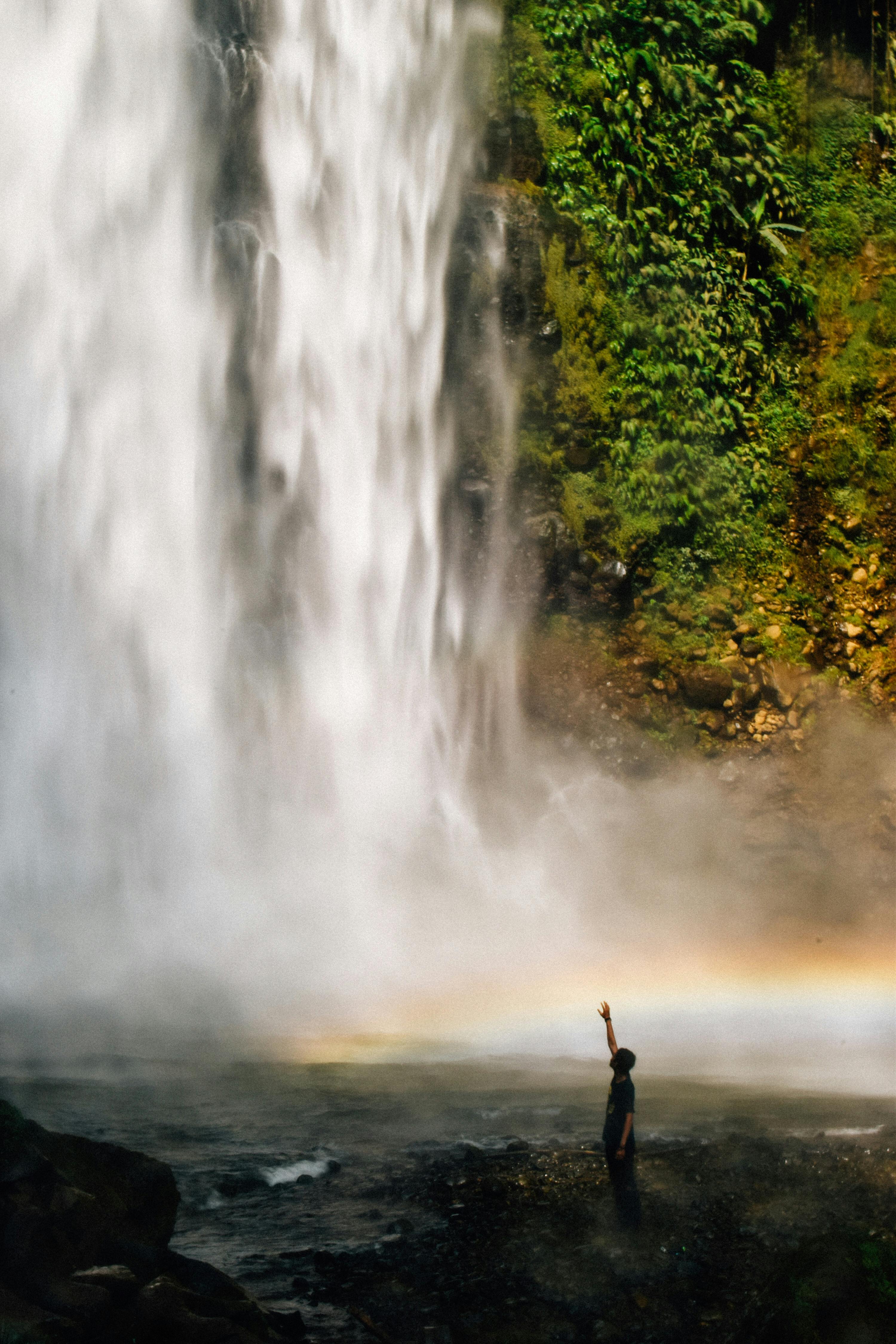 Low Angle Shot Of Woman Standing Under Waterfalls · Free Stock Photo