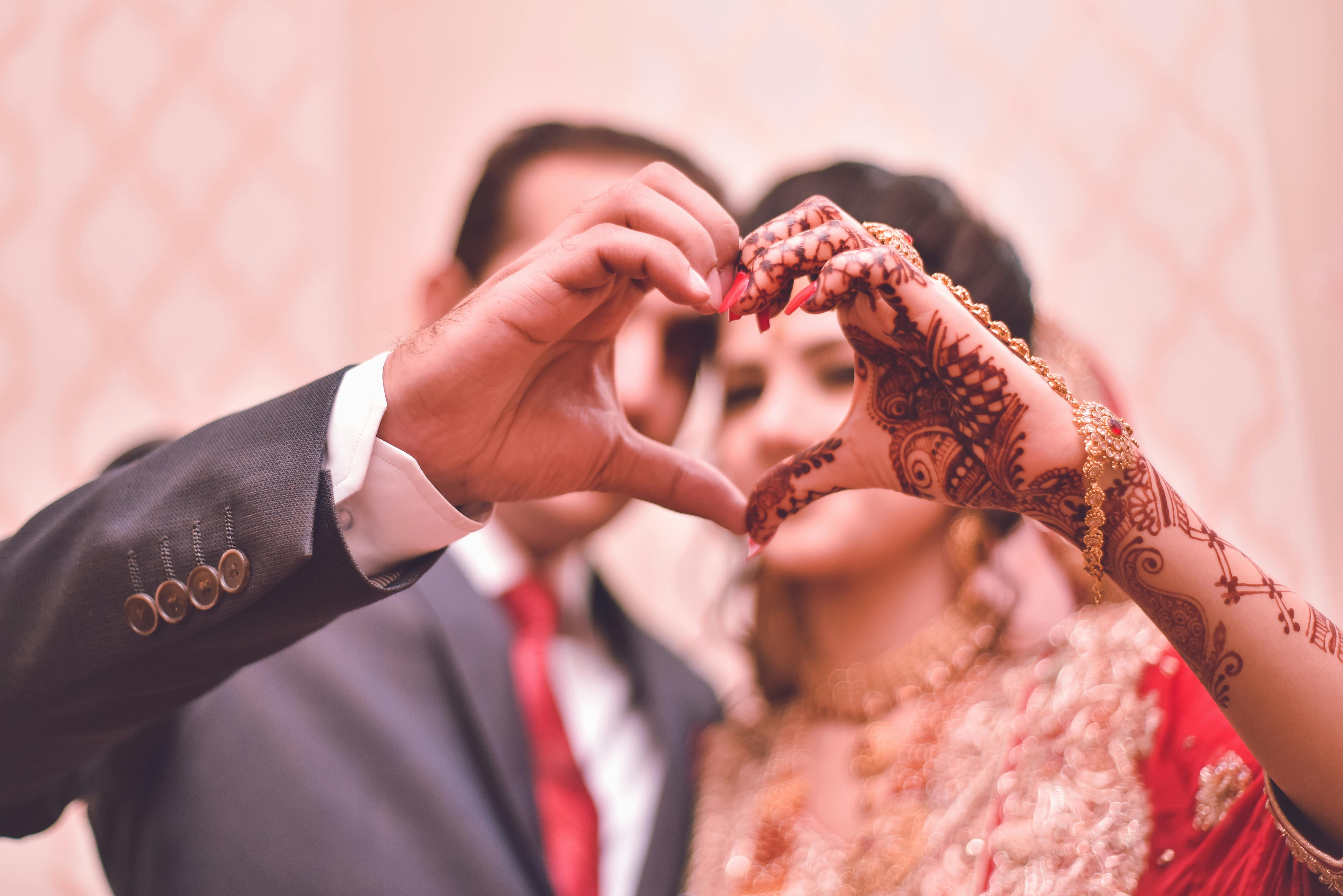 A Newlywed Couple Doing the Heart Sign Together · Free Stock Photo