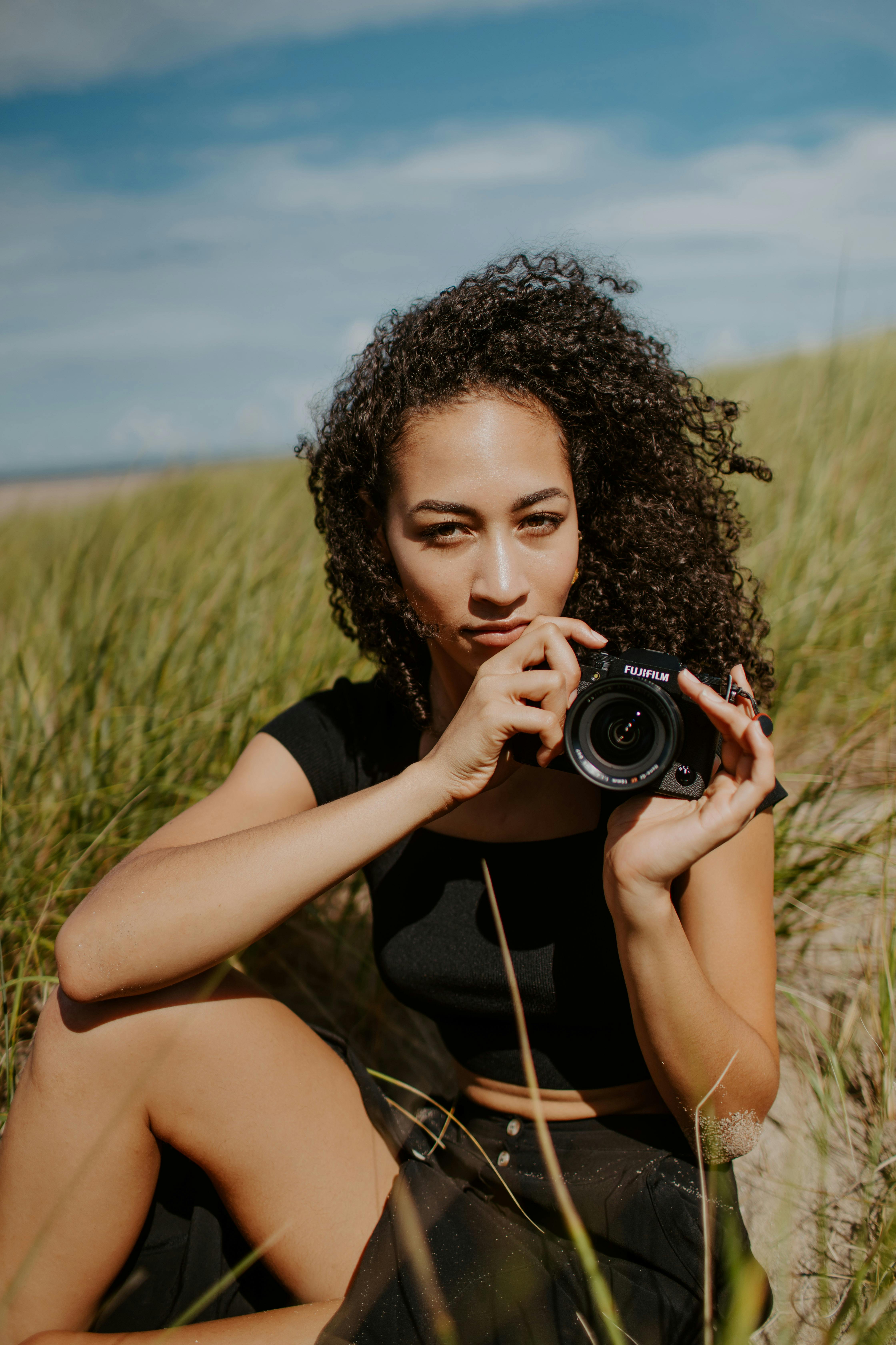 A Girl with Curly Hair Holding a Black Camera · Free Stock Photo