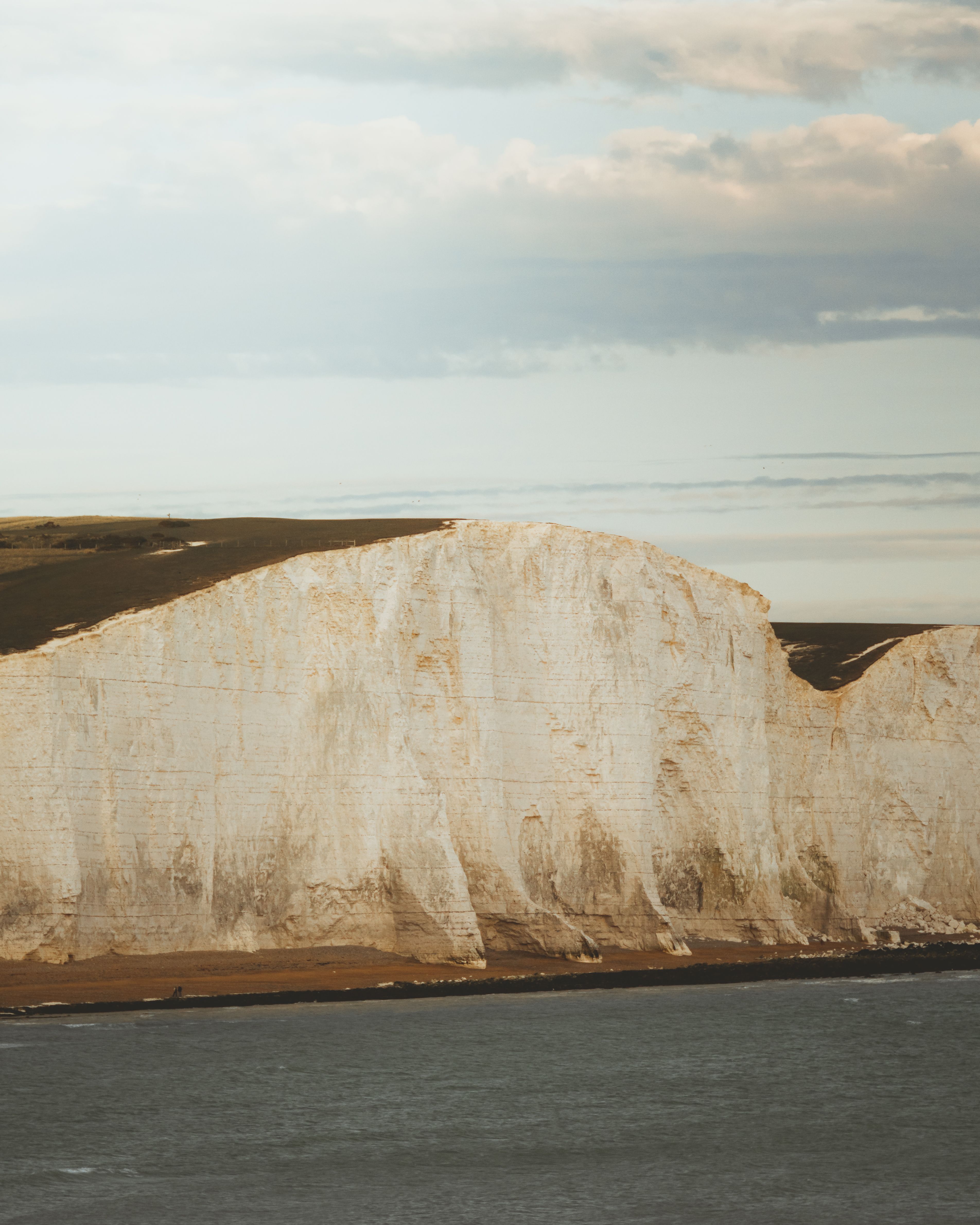 Rocky cliff against cloudy sky · Free Stock Photo