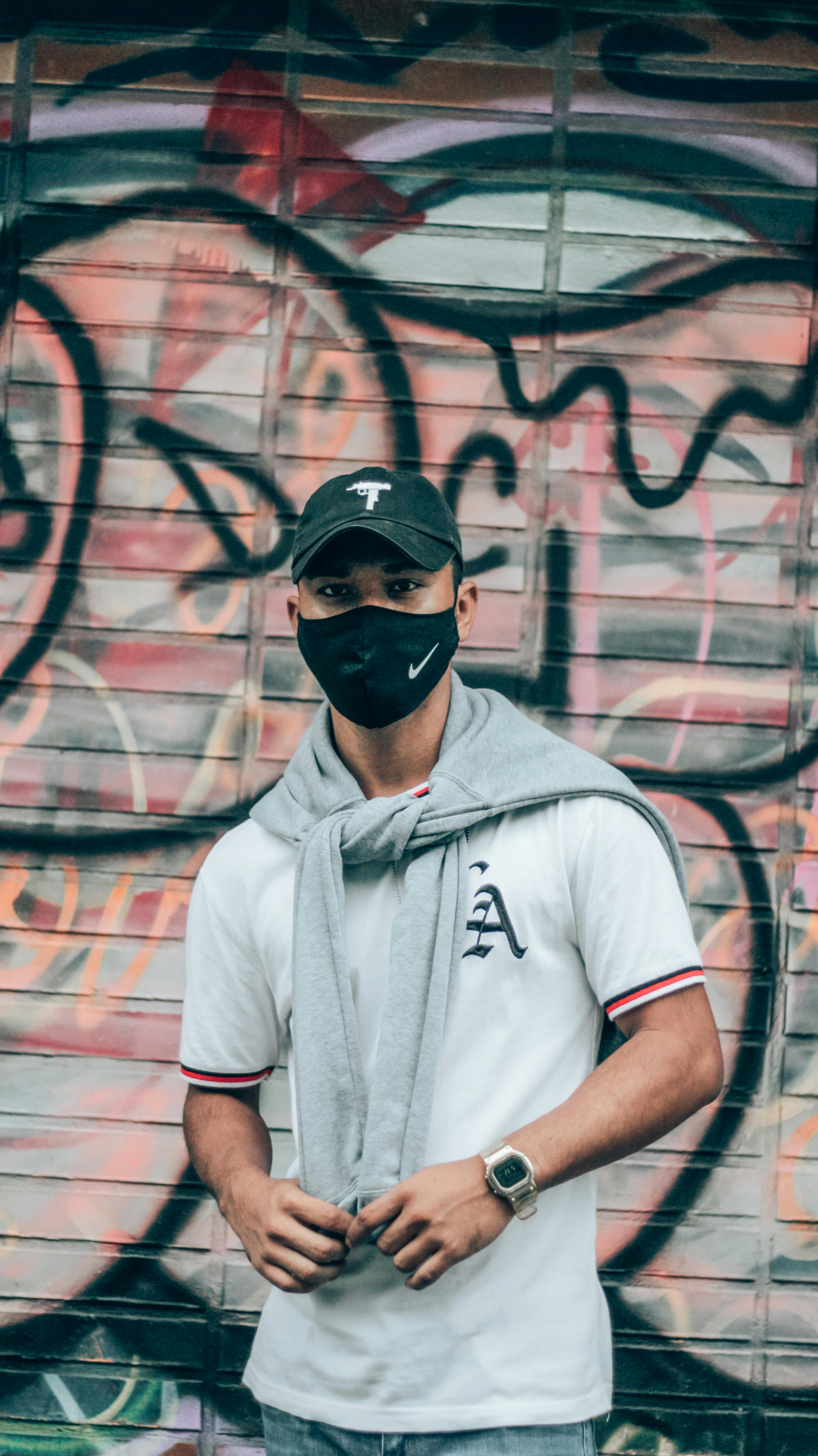 Man in a Face Mask Wearing a Baseball Cap Backwards · Free Stock Photo