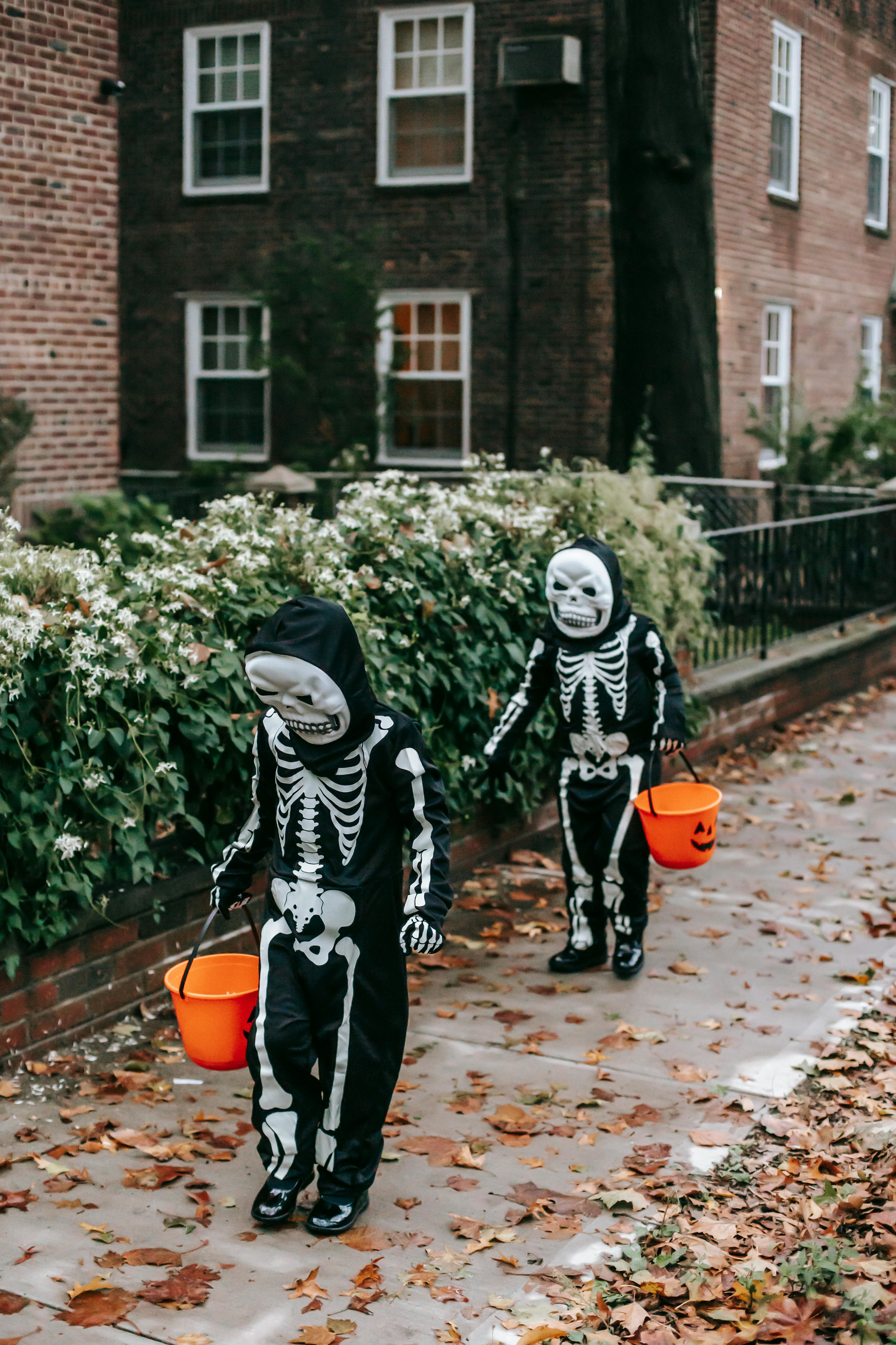 Anonymous little children in Halloween costumes walking in town Free Stock Photo