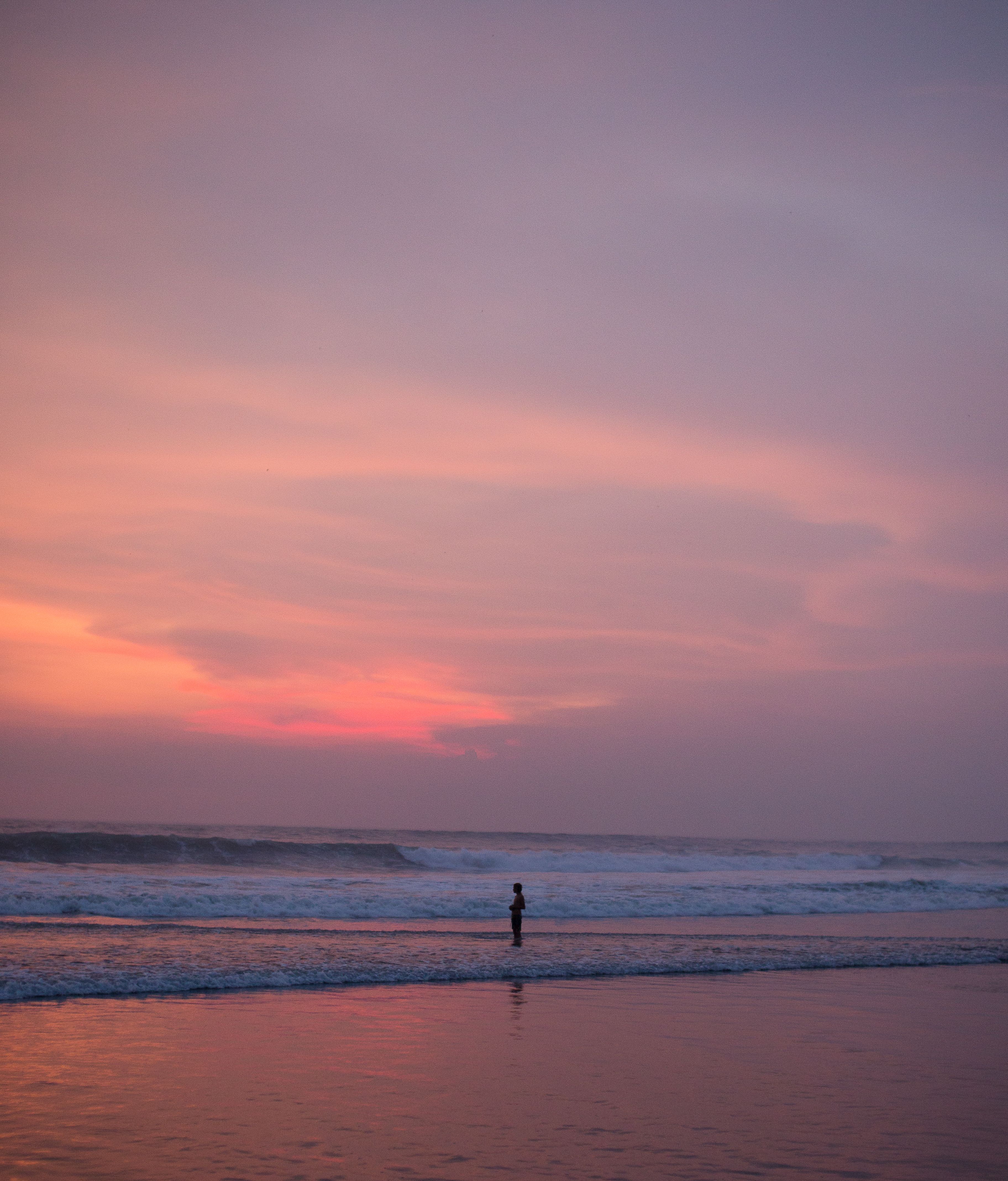 Person Standing on Beach During Sunset · Free Stock Photo