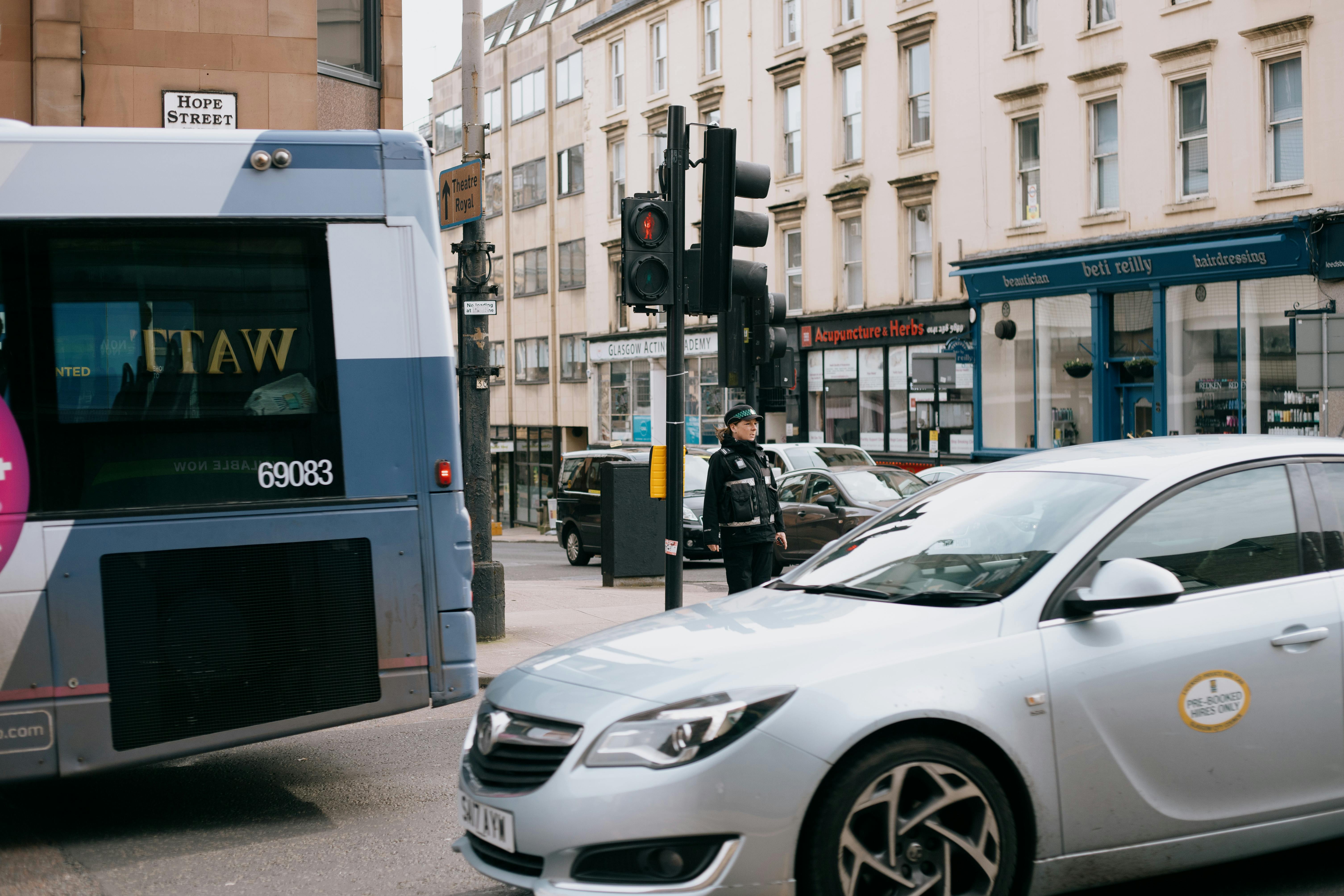 Modern bus and car on city road near building facades · Free Stock Photo