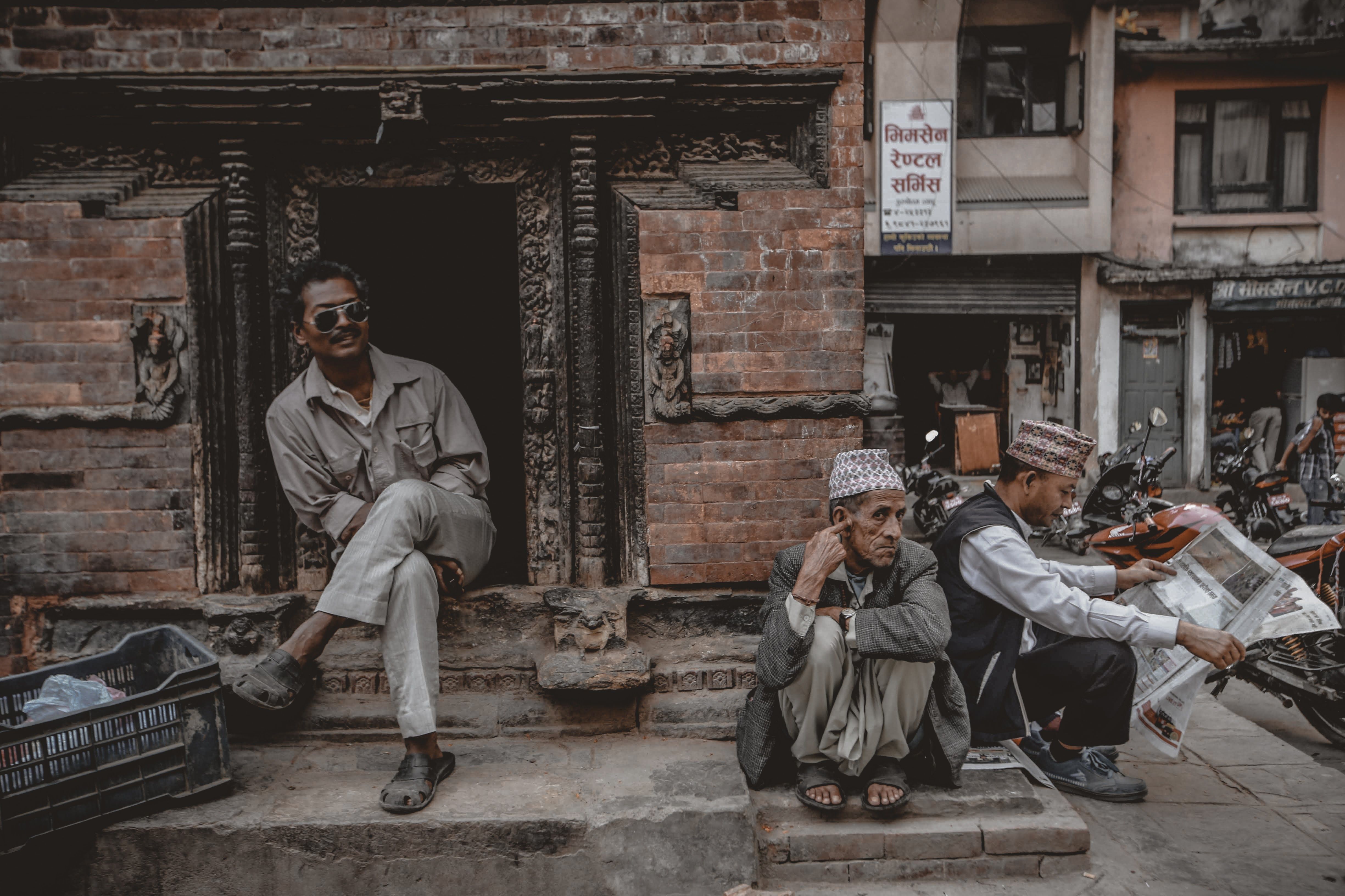 Asian men resting on ground on poor city street · Free Stock Photo