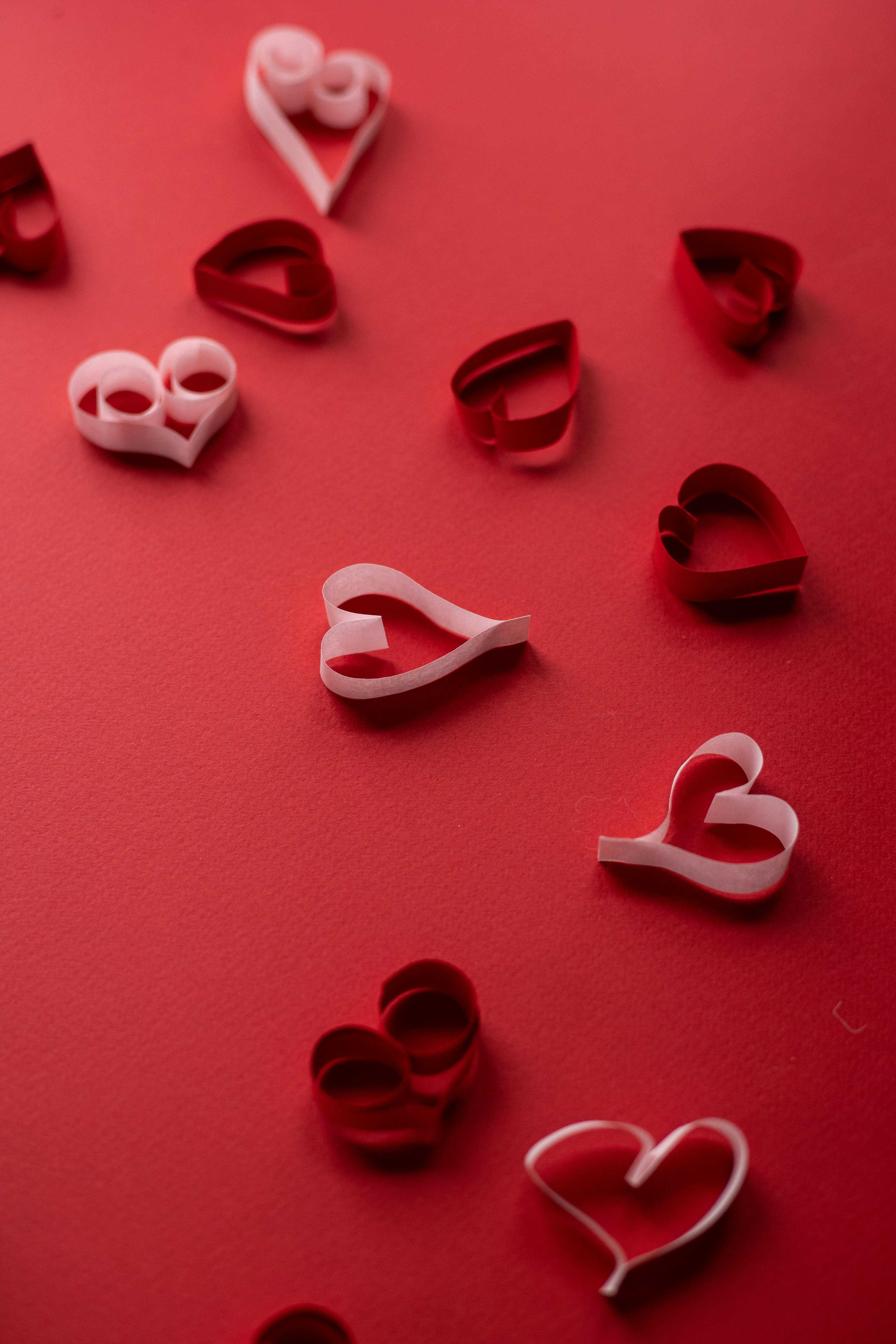 Paper confetti in heart shape on pink table · Free Stock Photo
