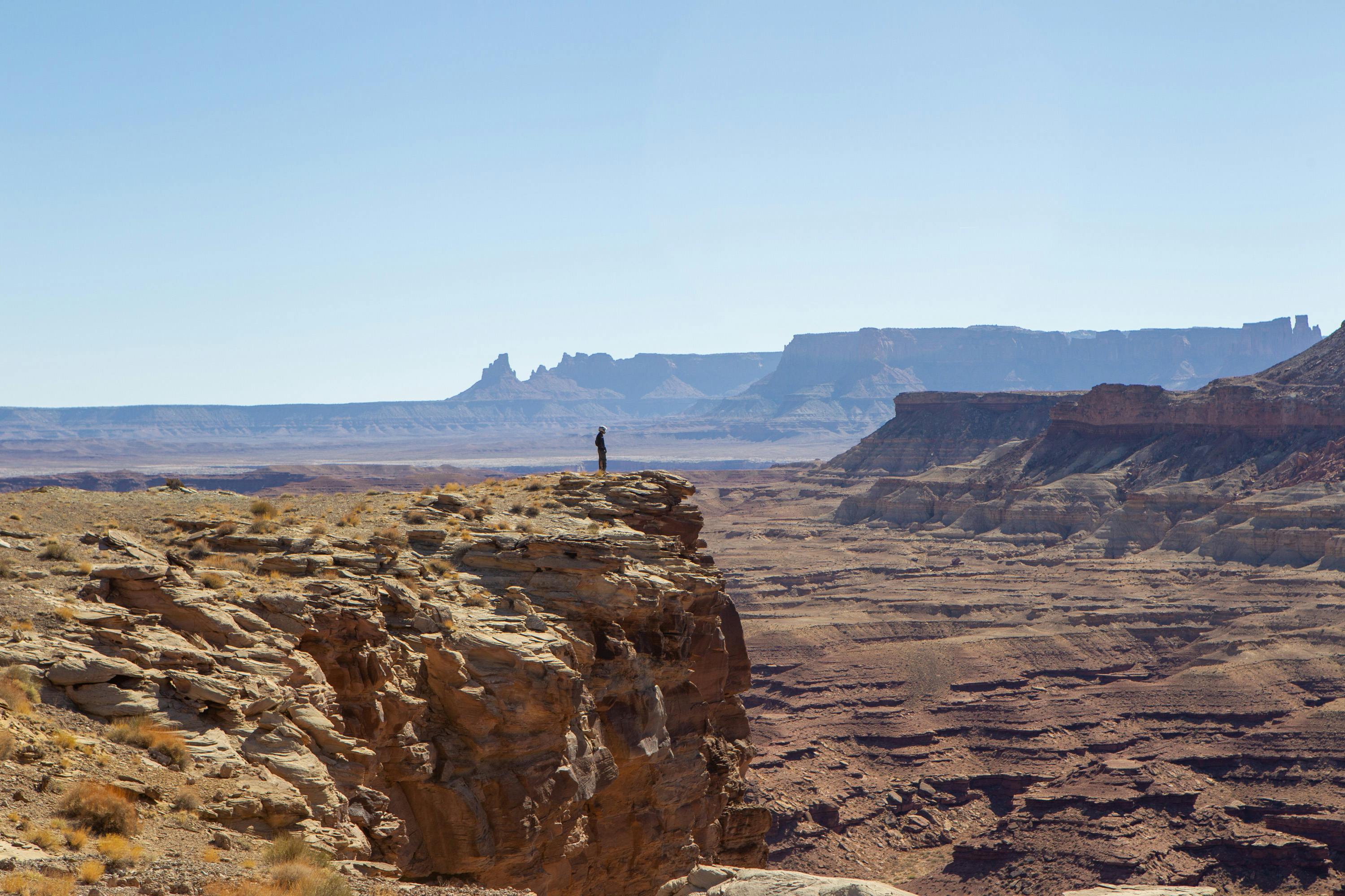 Person Standing on a Cliff of Brown Rock Mountain · Free Stock Photo