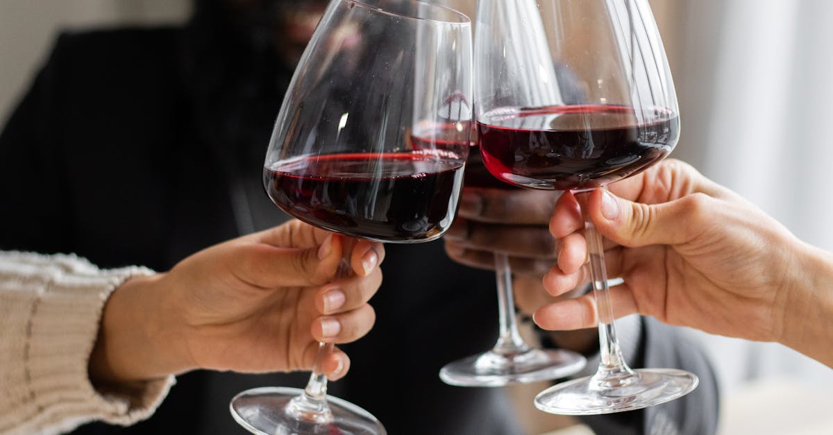 Crop cheerful diverse friends clinking glasses while having dinner ... Crop cheerful diverse friends clinking glasses while having dinner ...