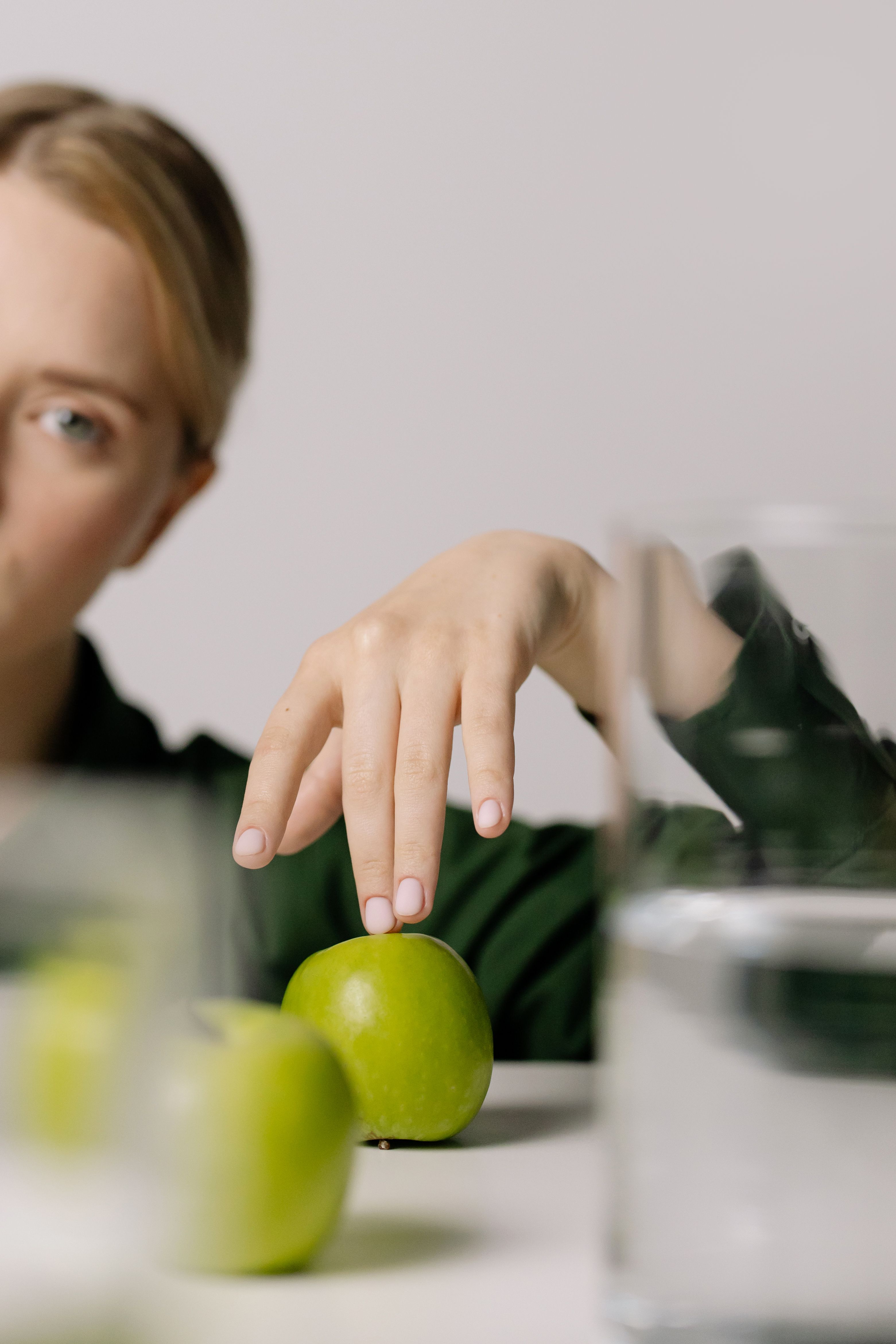 Woman in Green Long Sleeves Touching the Green Apple on the White ...