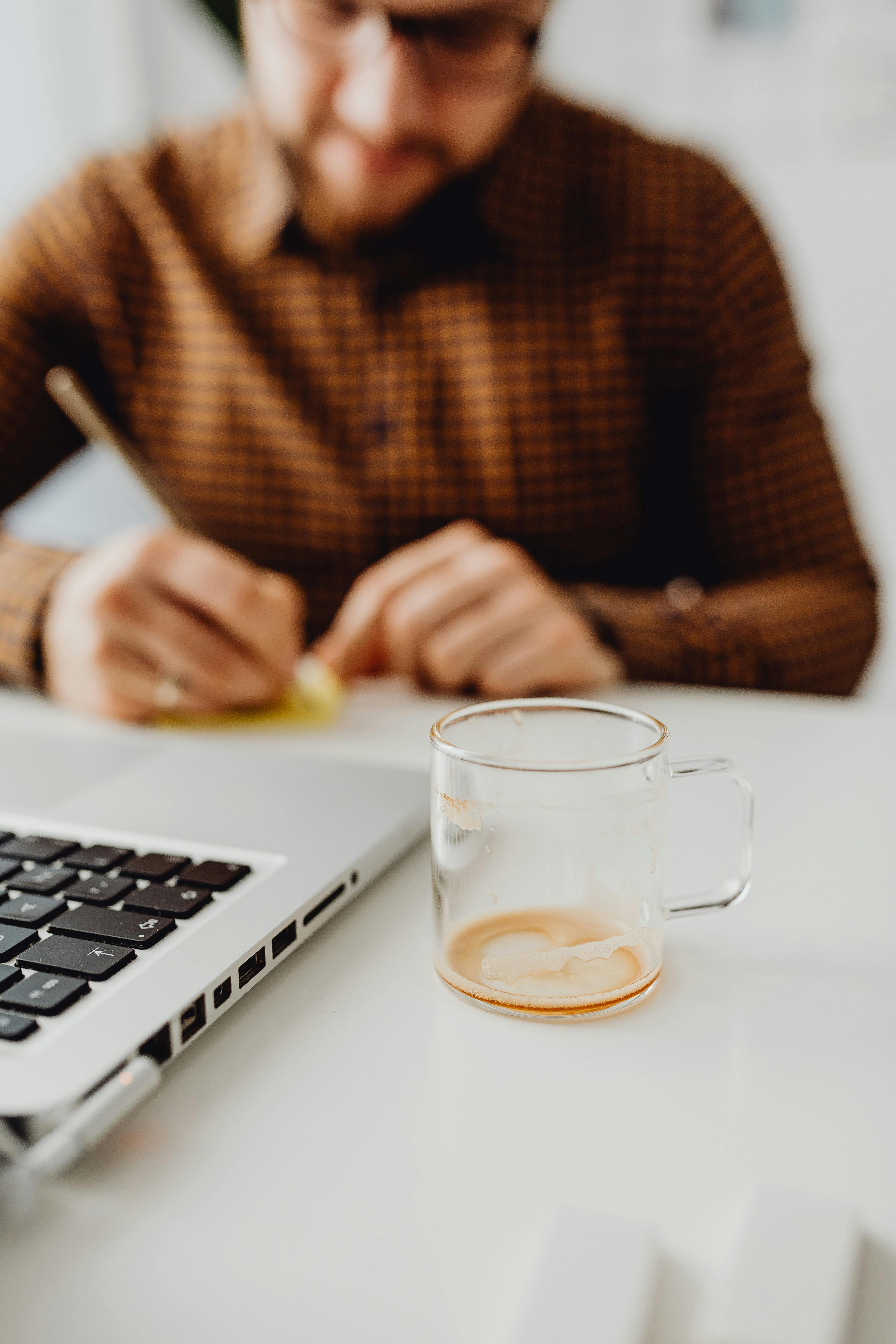 Person Writing On A Notebook Beside Macbook · Free Stock Photo